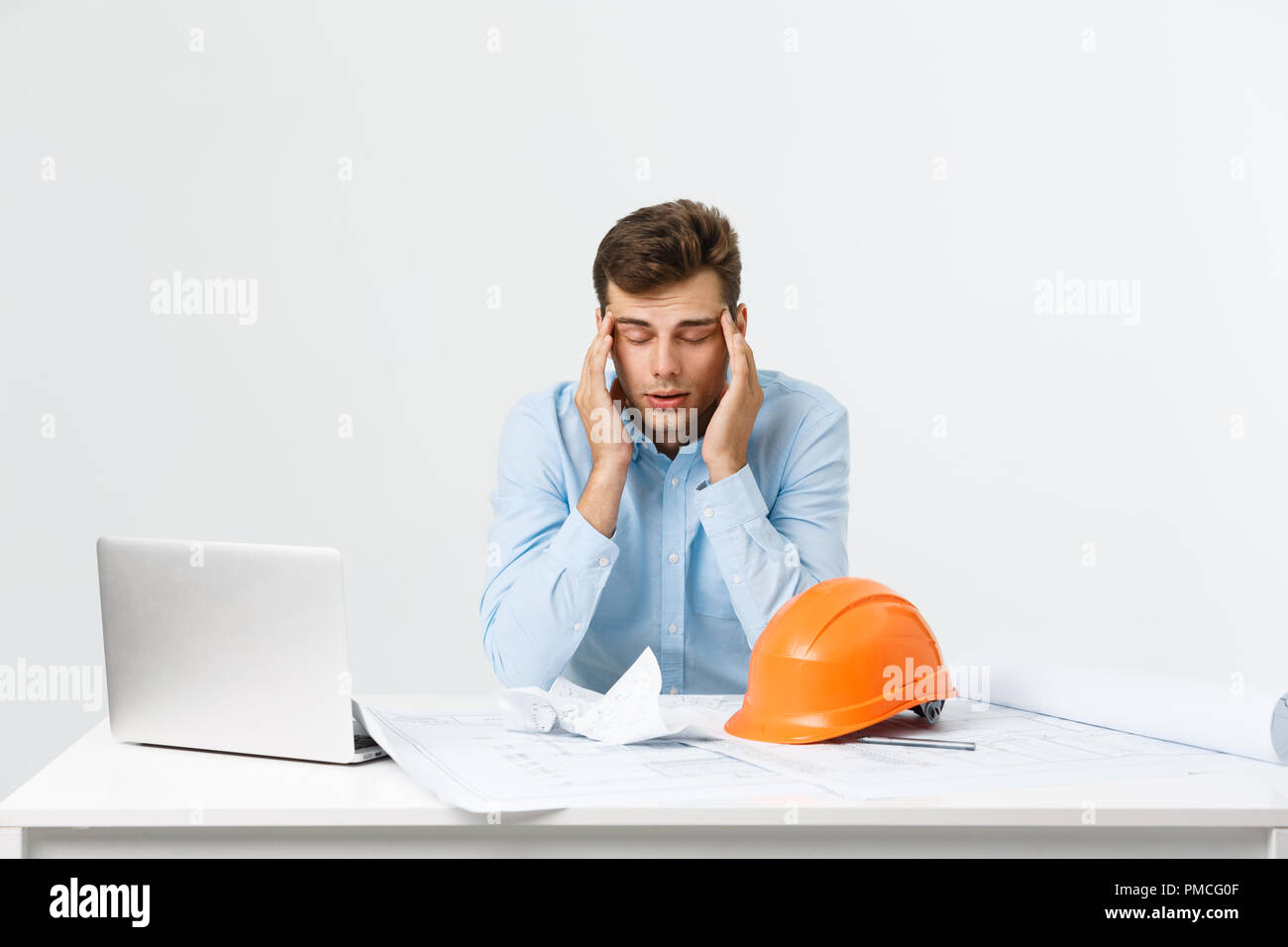 Portrait of engineer stress holding his head with hand sitting at the ...