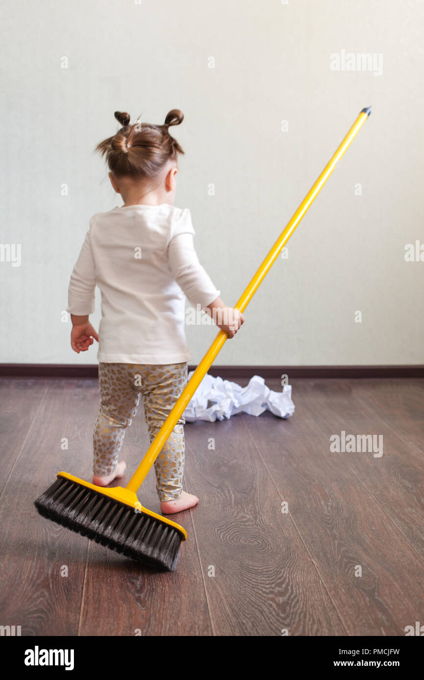 the child stands with his back to the camera, holds the broom in his ...