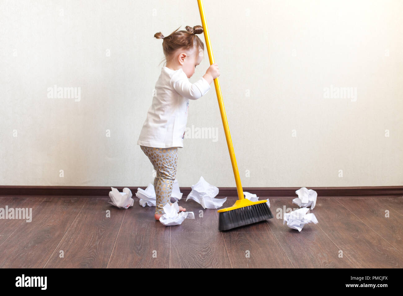 child sweeps broom with paper bins in the apartment, household chores ...