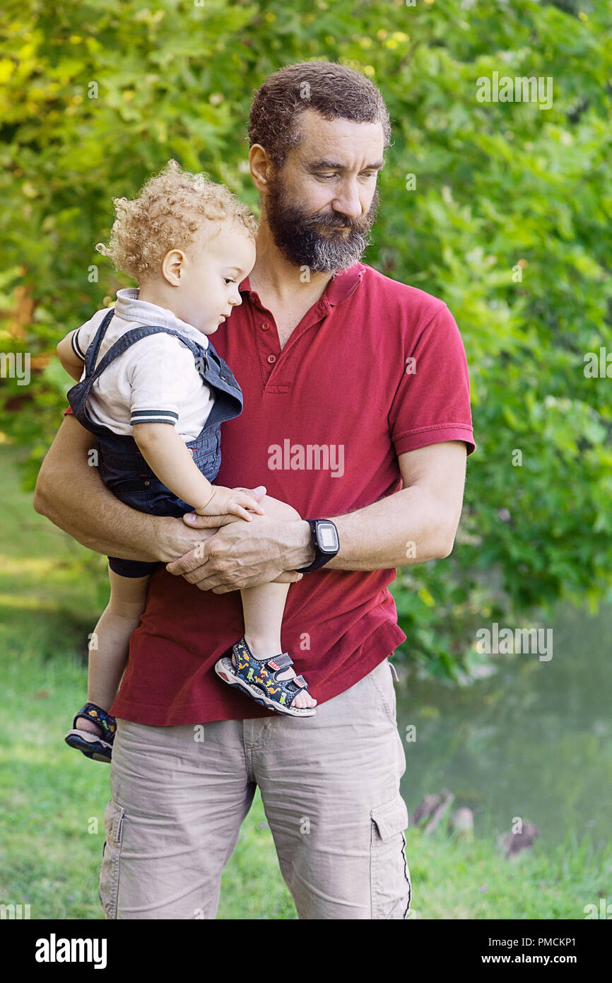 Father holding his son in the park. Parental protection. Summer fun in ...