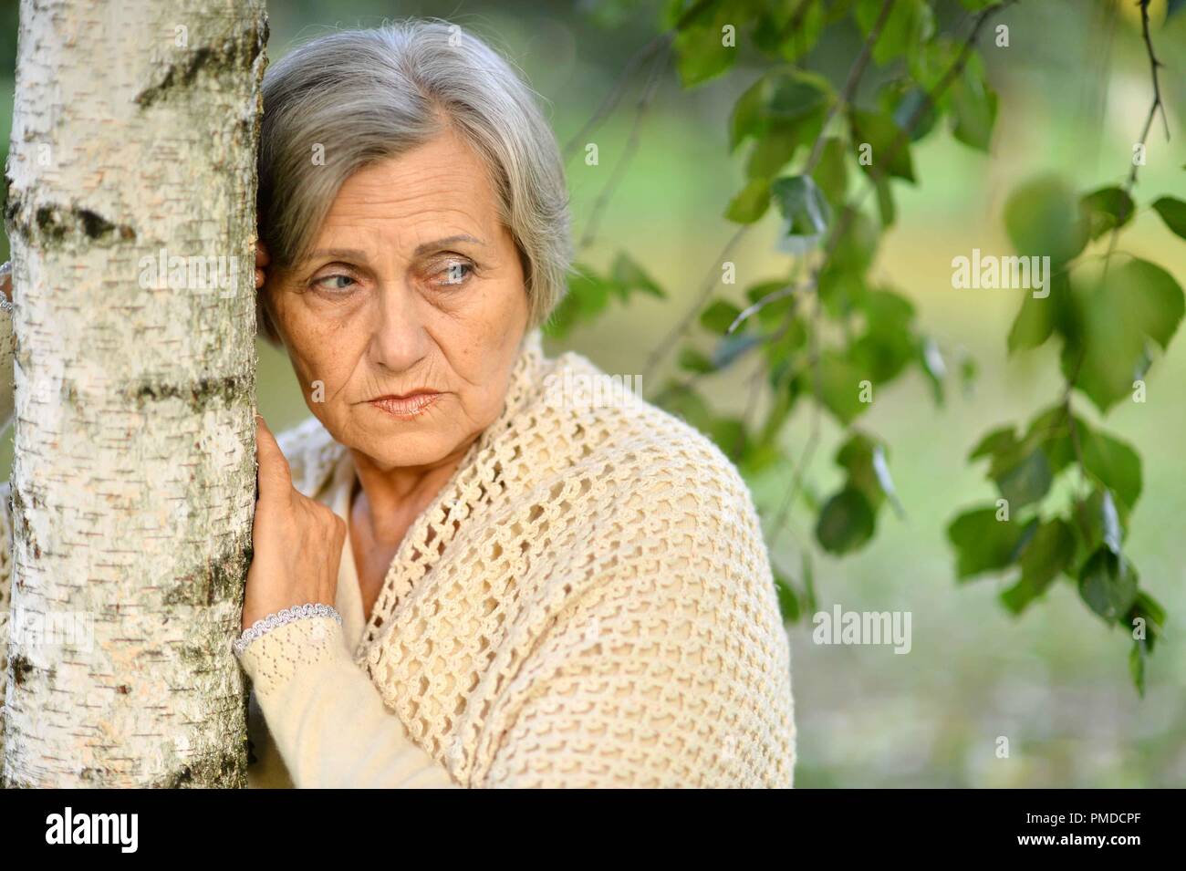 Nice happy old woman standing by the tree Stock Photo - Alamy