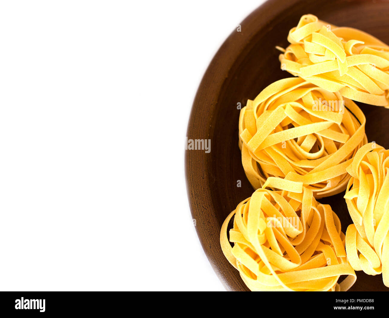 Uncooked tagliatelle on ceramic plate. Isolated Stock Photo - Alamy