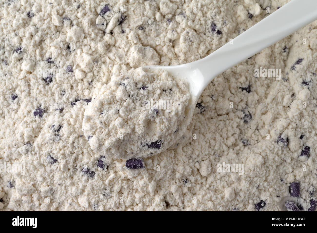 Top view of a white plastic spoon with a spoonful of clumpy blueberry ...