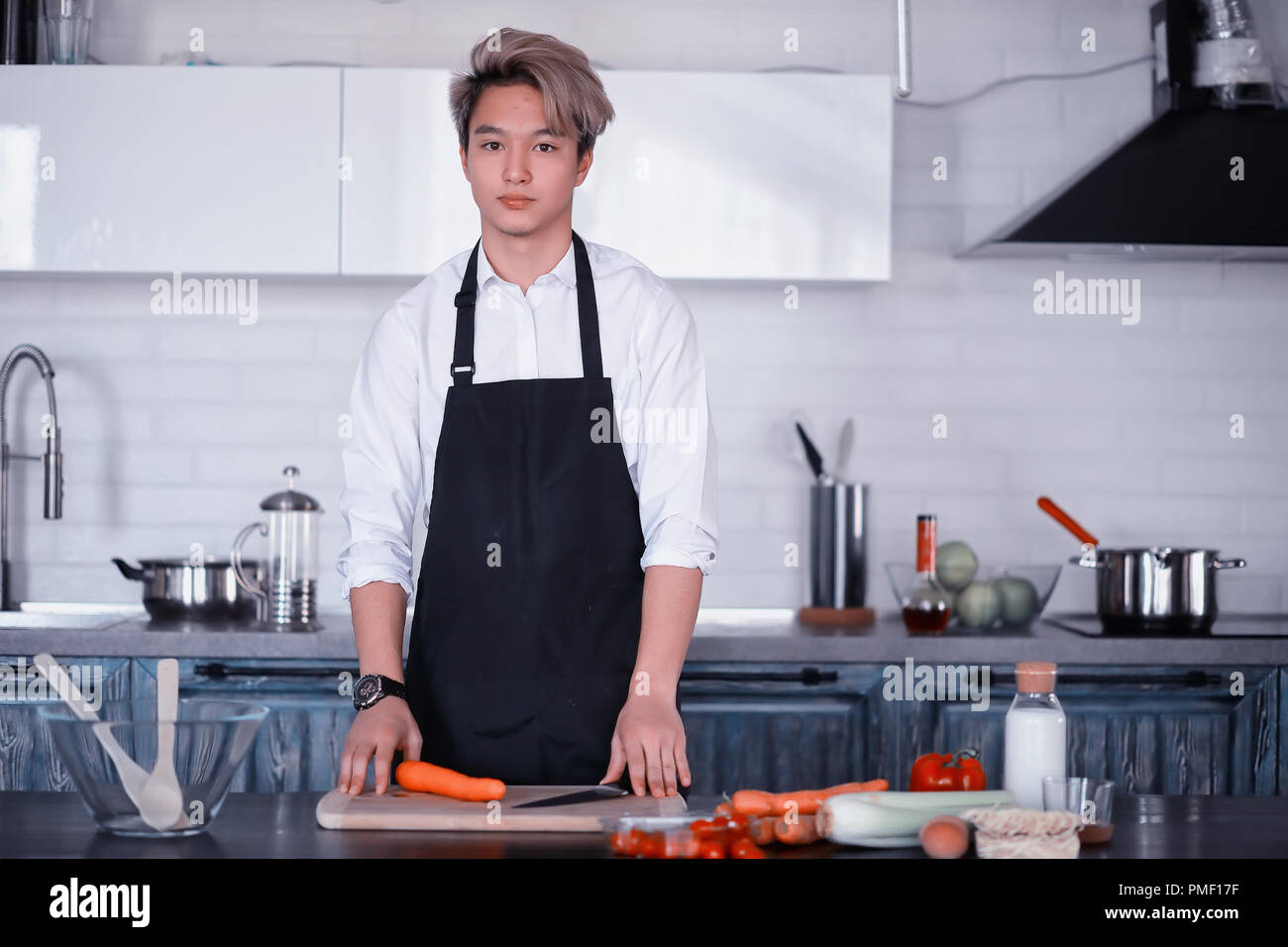 Asian cook in the kitchen prepares food in a cook suit Stock Photo - Alamy