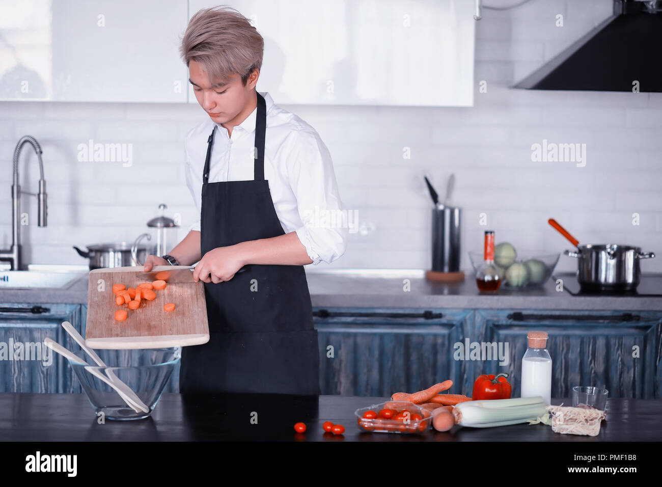 Asian cook in the kitchen prepares food in a cook suit Stock Photo - Alamy