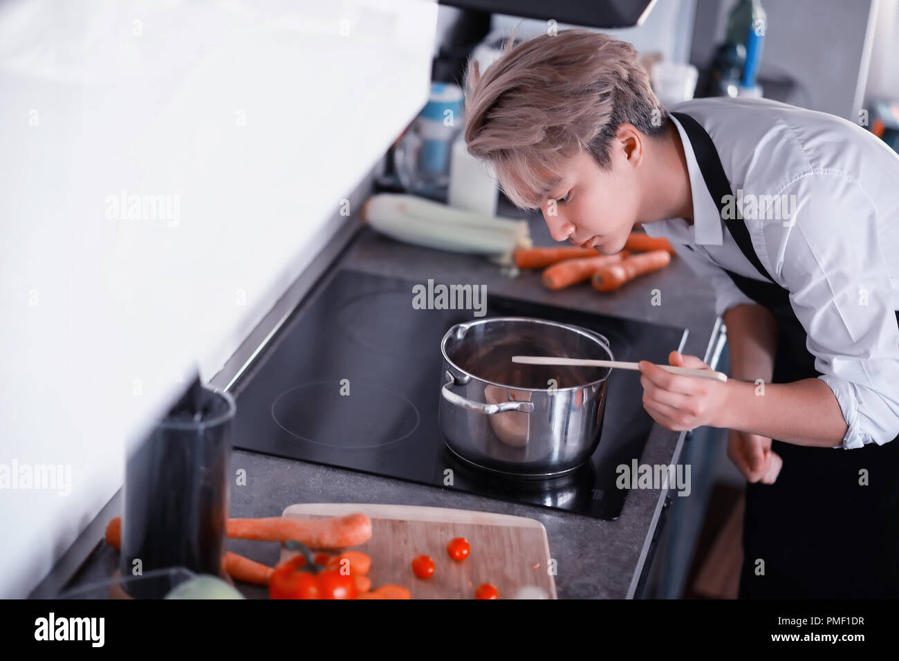 Asian cook in the kitchen prepares food in a cook suit Stock Photo - Alamy