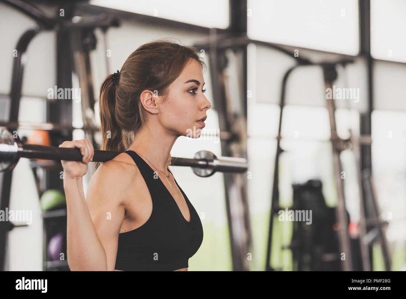 Cute girl has a hard athletic workout in the gym, doing exercises with ...