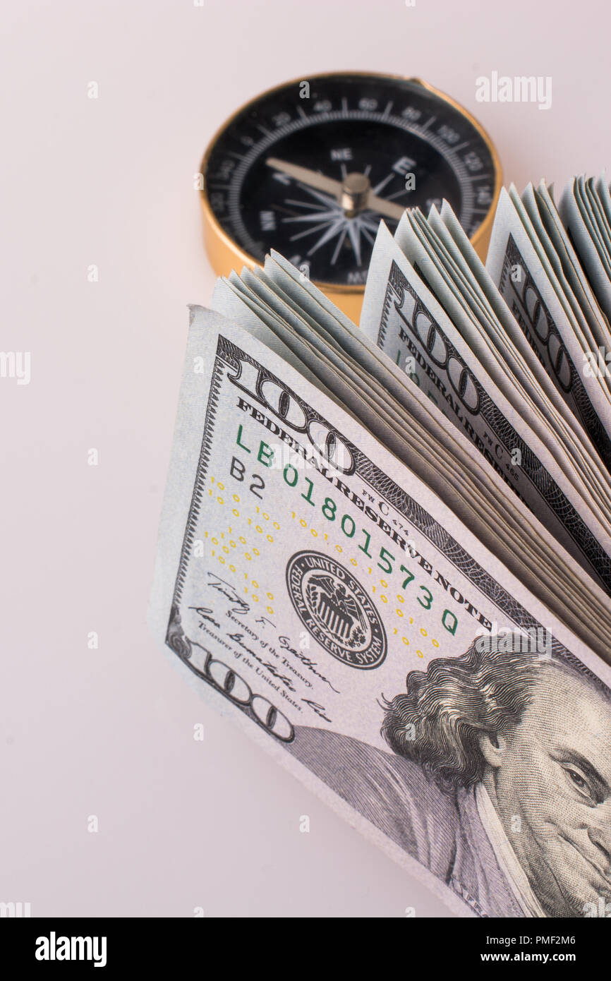 American dollar banknotes by the side of a compass on white background ...