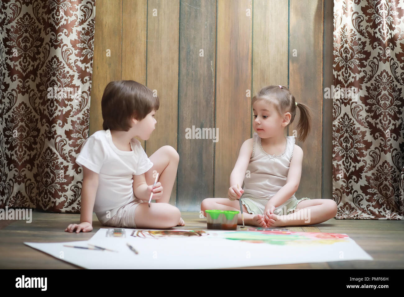 Little children paint on a large sheet of paper Stock Photo - Alamy