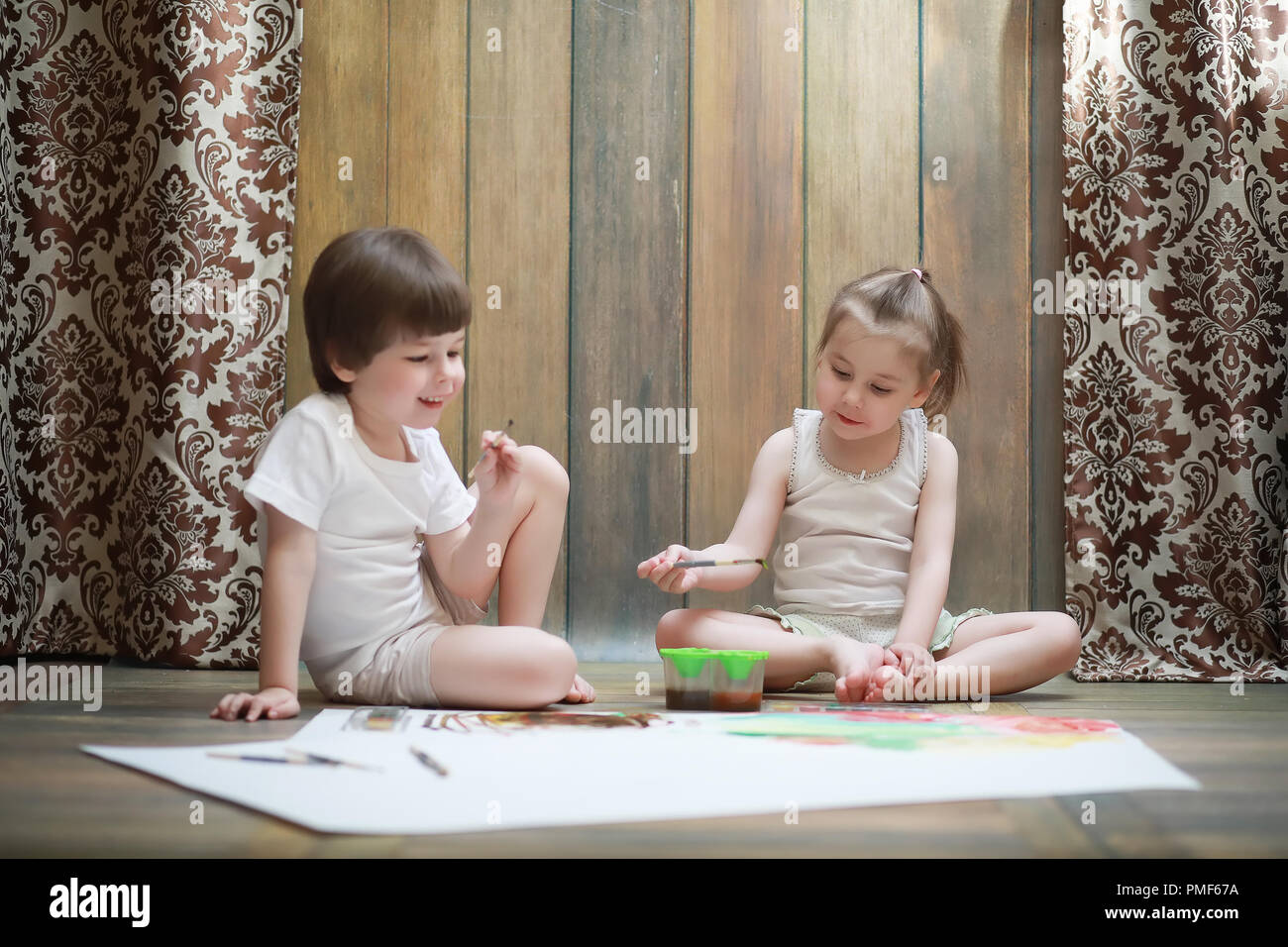 Little children paint on a large sheet of paper Stock Photo - Alamy