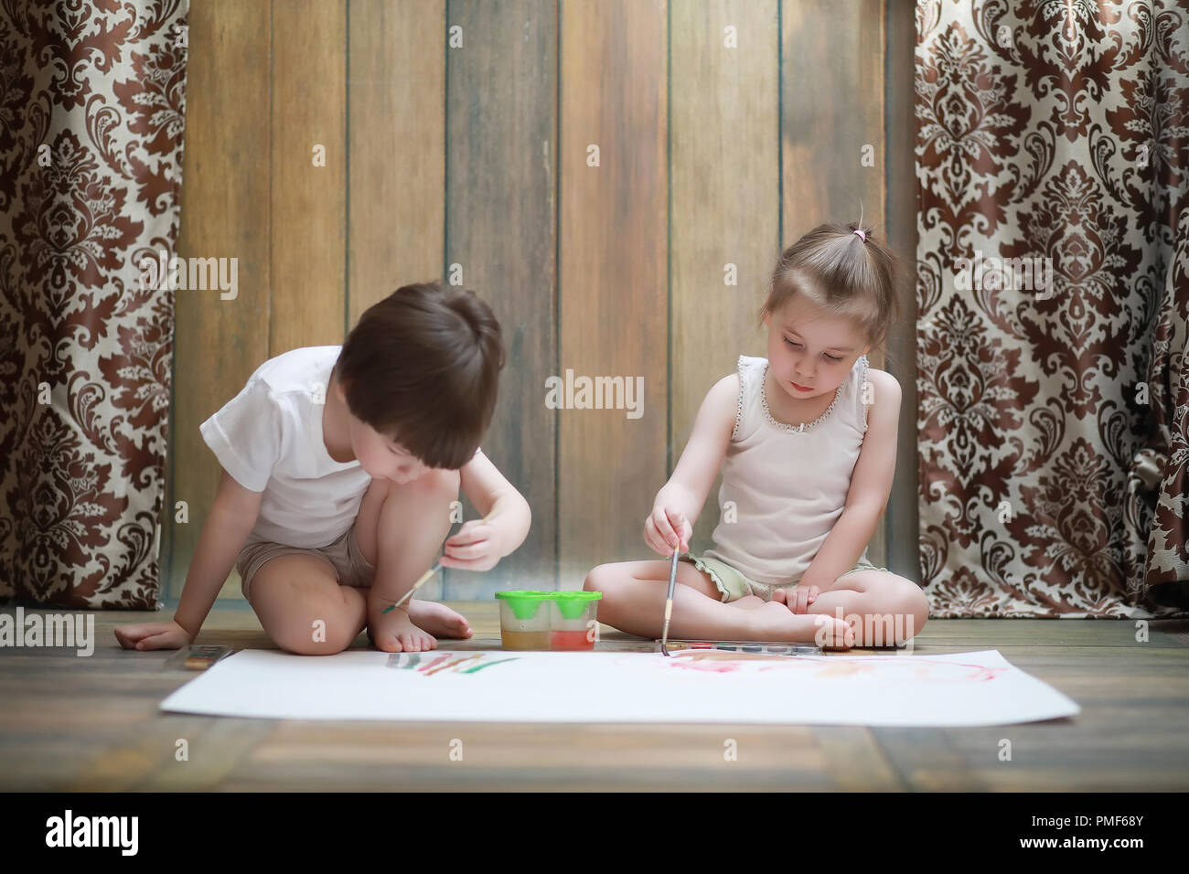 Little children paint on a large sheet of paper Stock Photo - Alamy