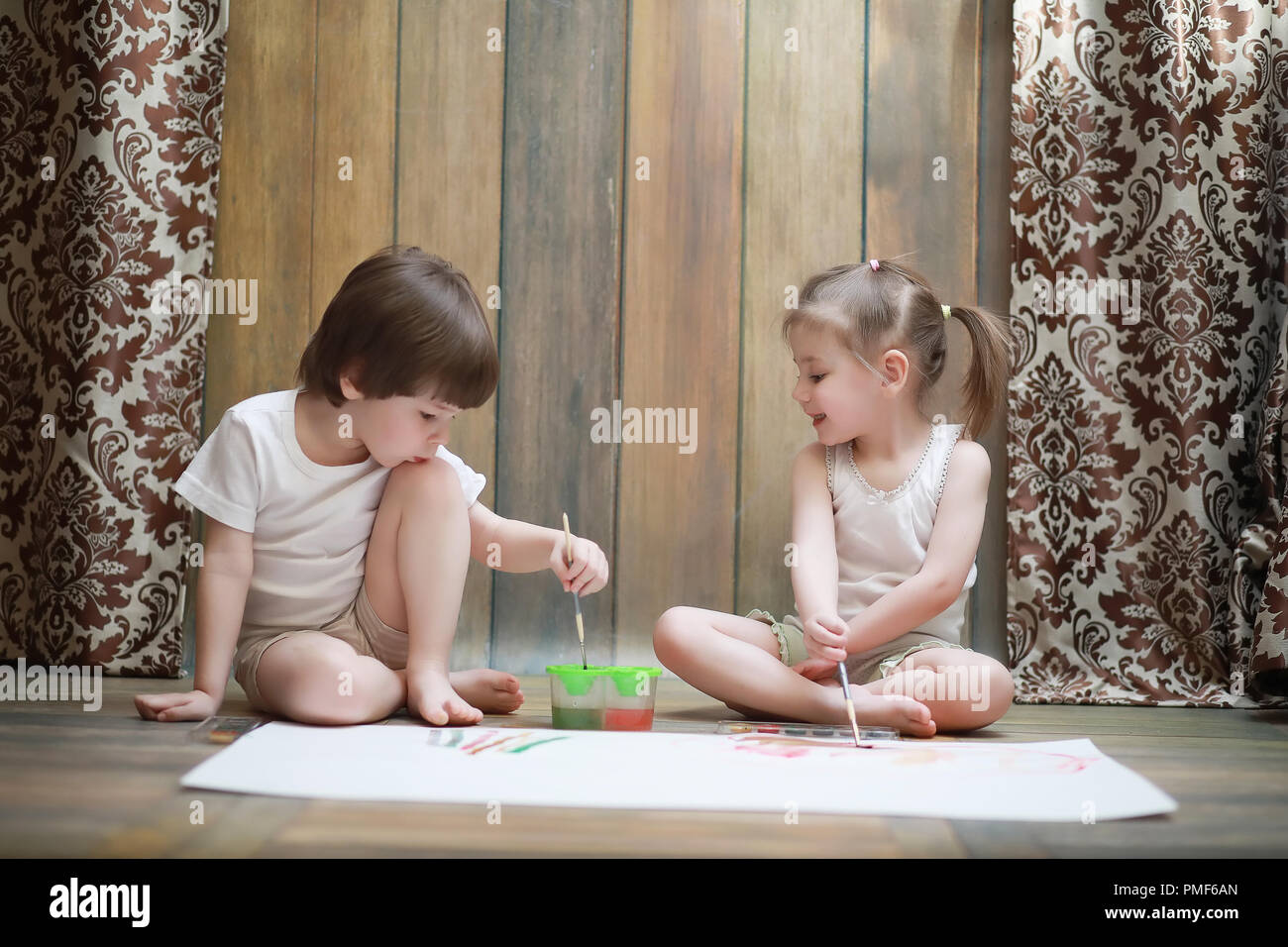 Little children paint on a large sheet of paper Stock Photo - Alamy