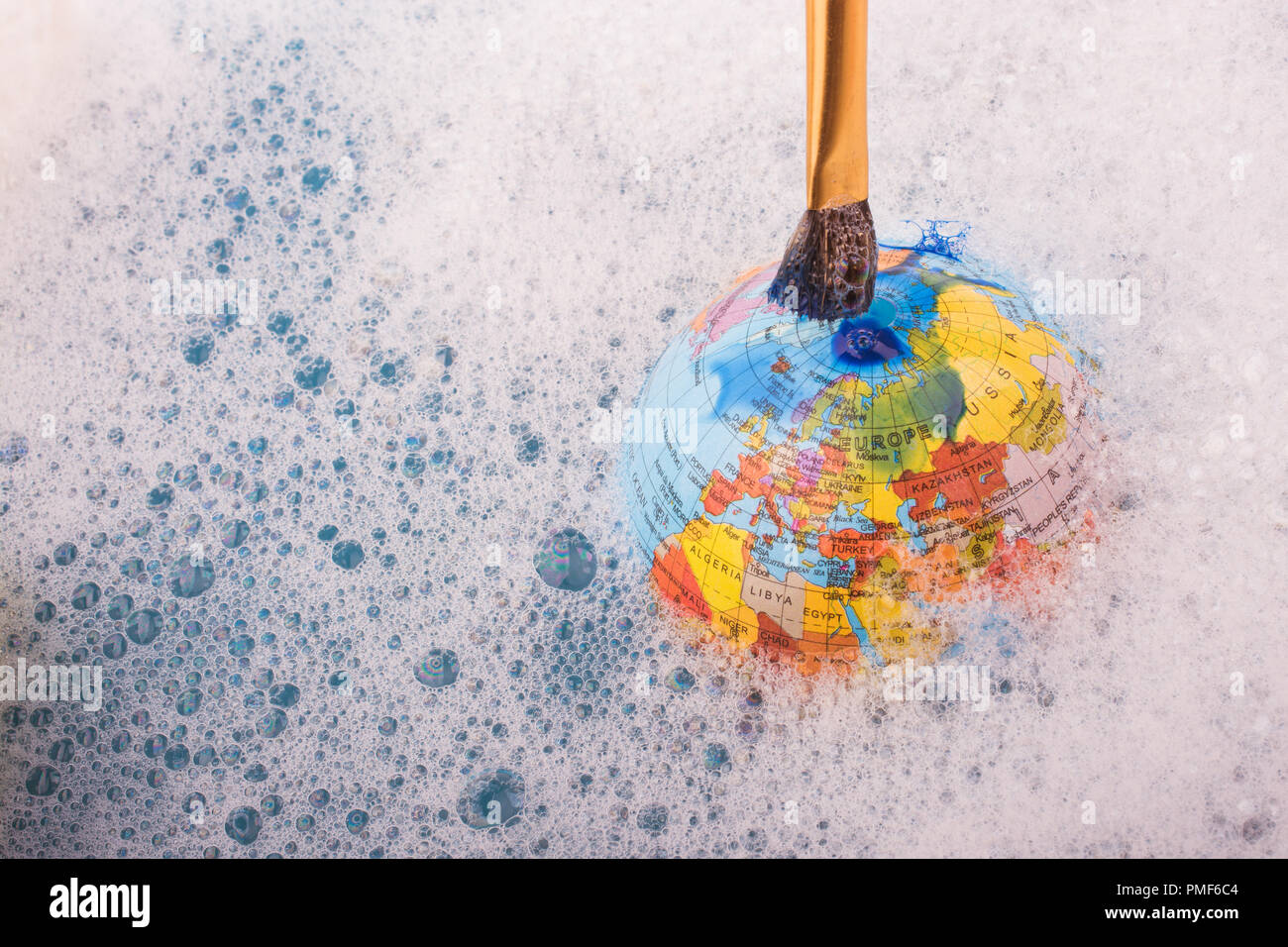 Paint dissolving through painting brush on the top of globe Stock Photo ...