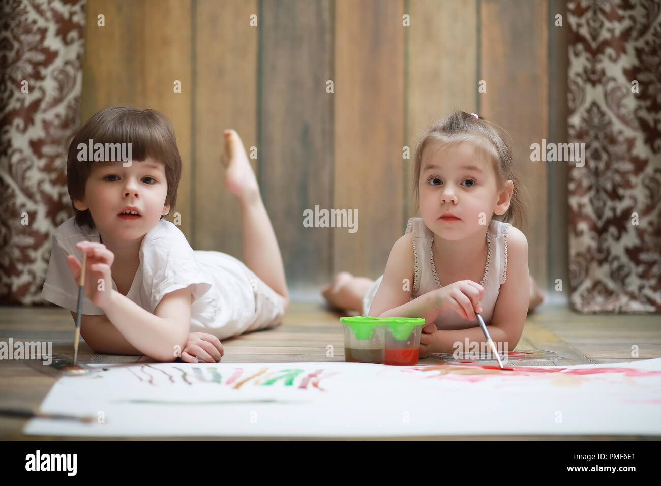 Little children paint on a large sheet of paper Stock Photo - Alamy