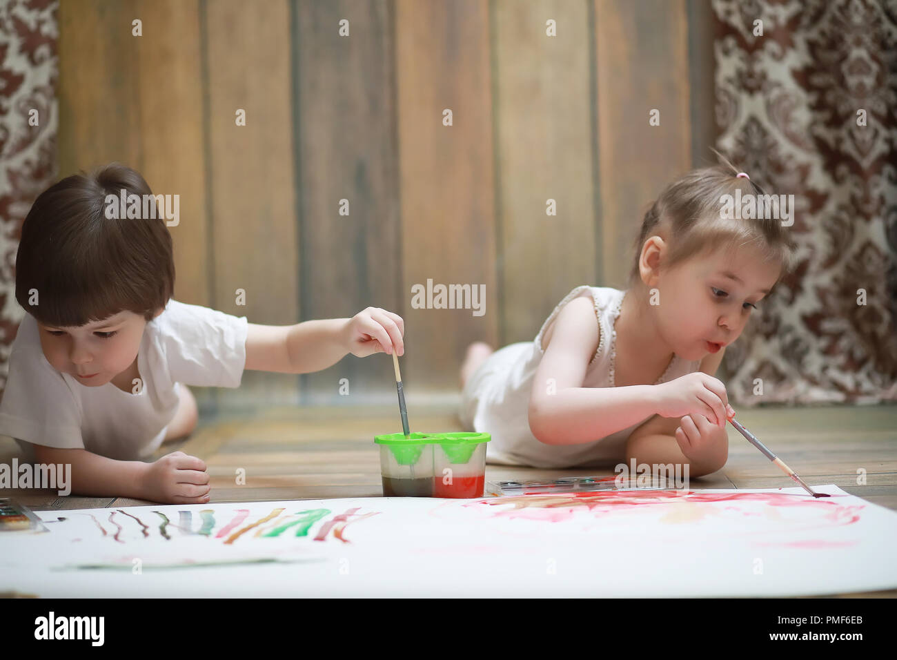 Little children paint on a large sheet of paper Stock Photo - Alamy