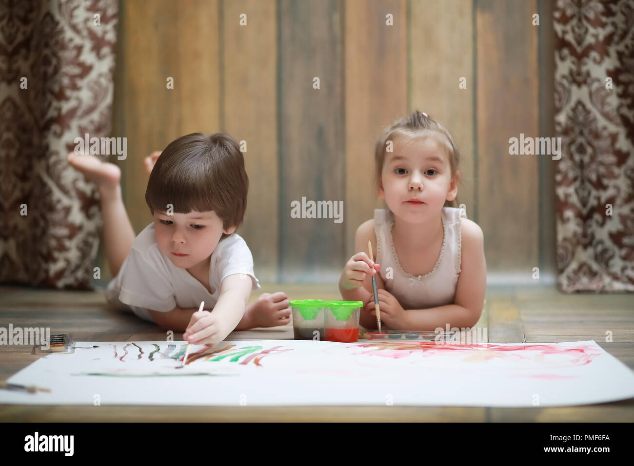 Little children paint on a large sheet of paper Stock Photo - Alamy