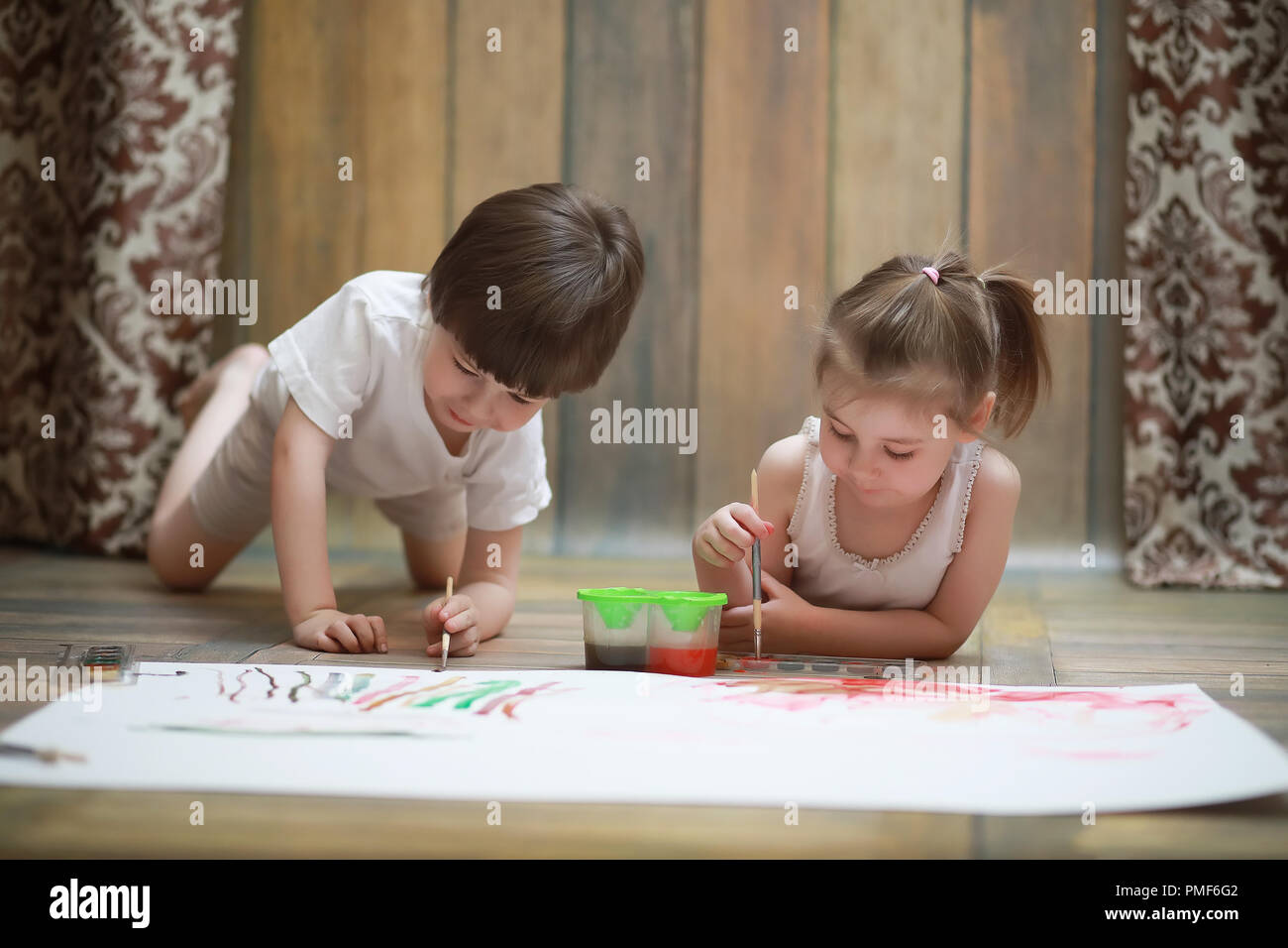 Little children paint on a large sheet of paper Stock Photo - Alamy