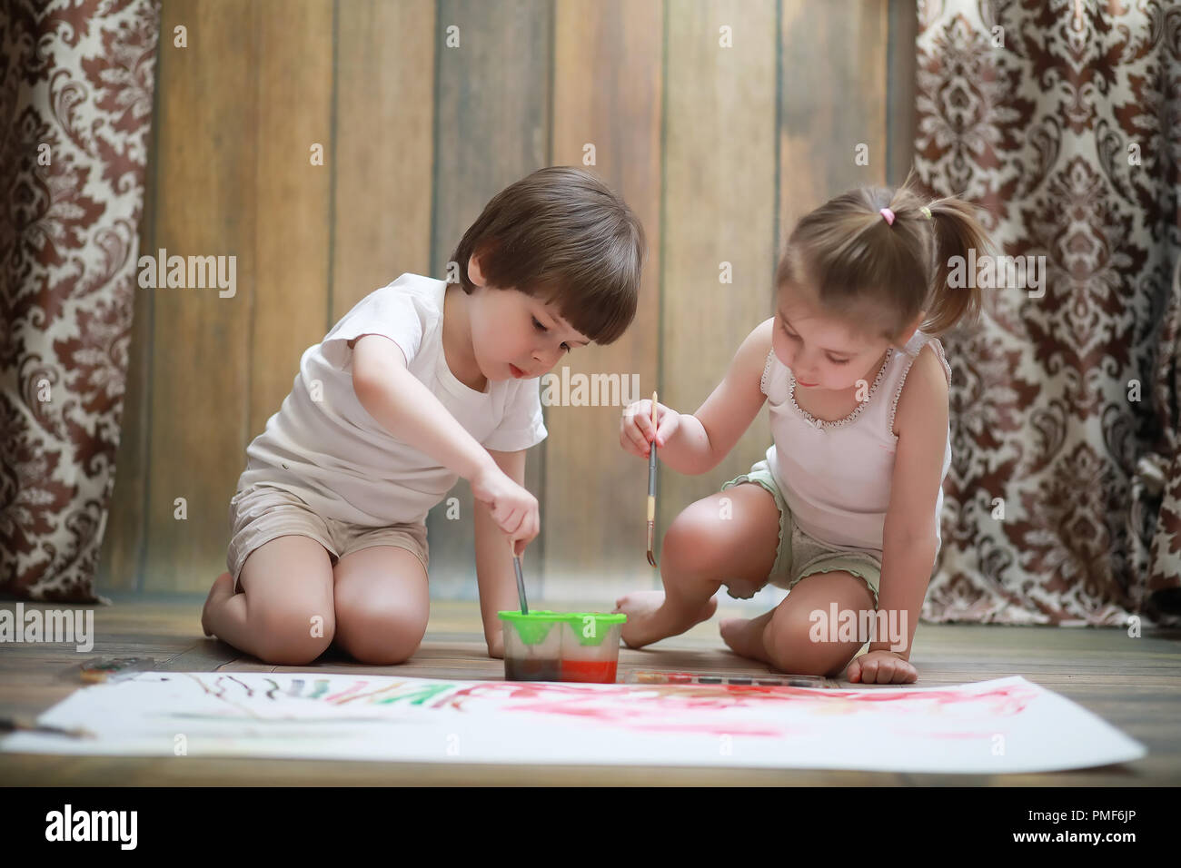 Little children paint on a large sheet of paper Stock Photo - Alamy