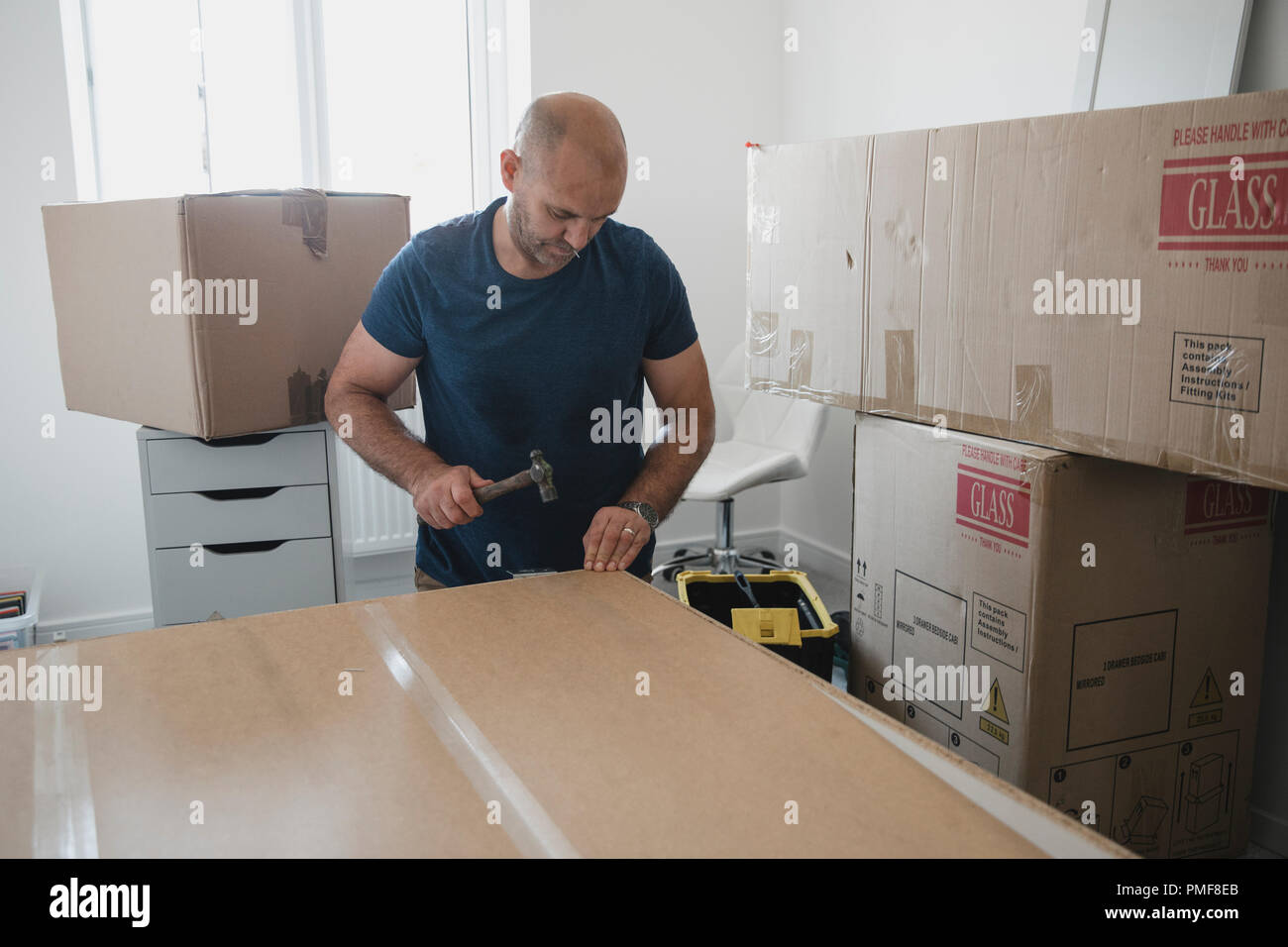 Mature man is putting a wardrobe together in a bedroom of a new home ...