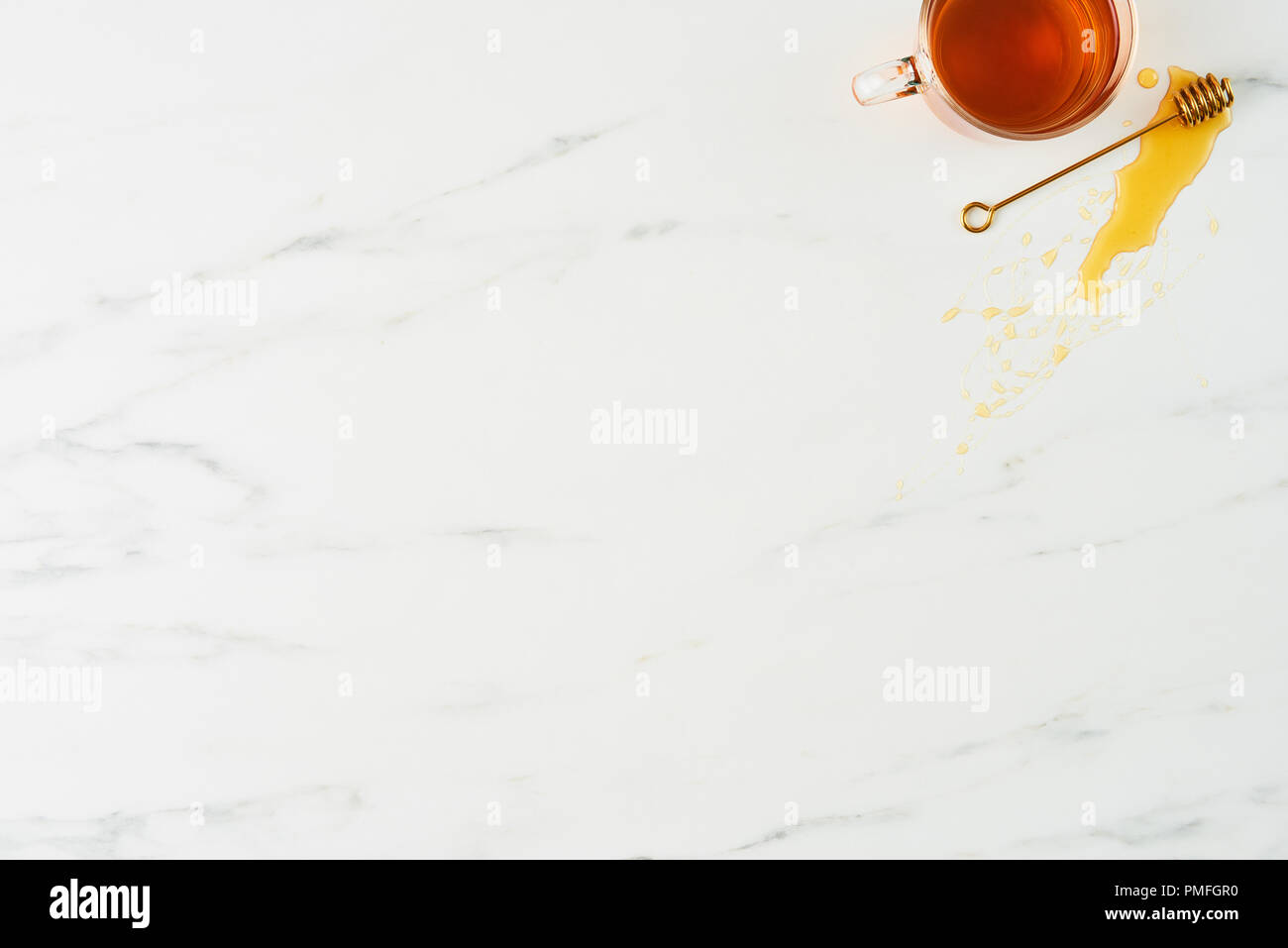 Tea concept. Top view of tea in glass cup and golden dipper with honey ...