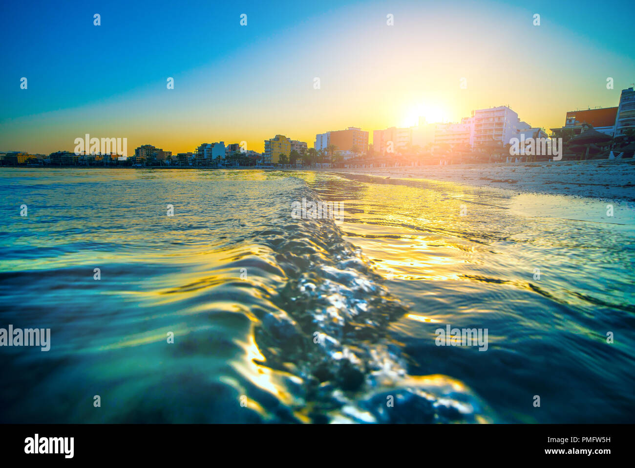Wavy curves of sea is covered in golden sunset light. Sea at sunset ...