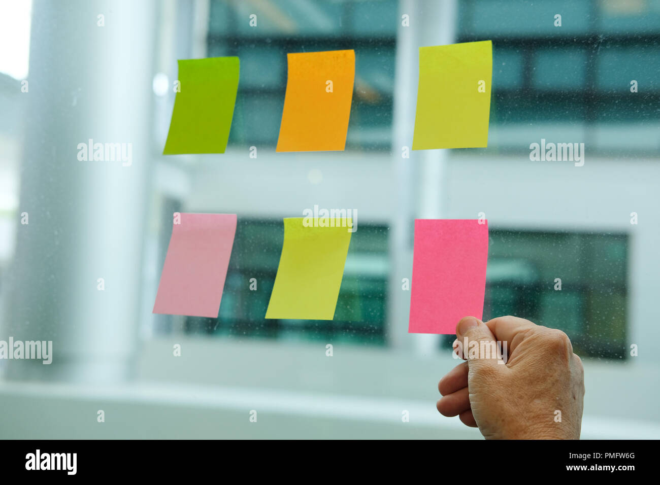hand hold adhesive notes on glass wall at workplace. Sticky note paper ...