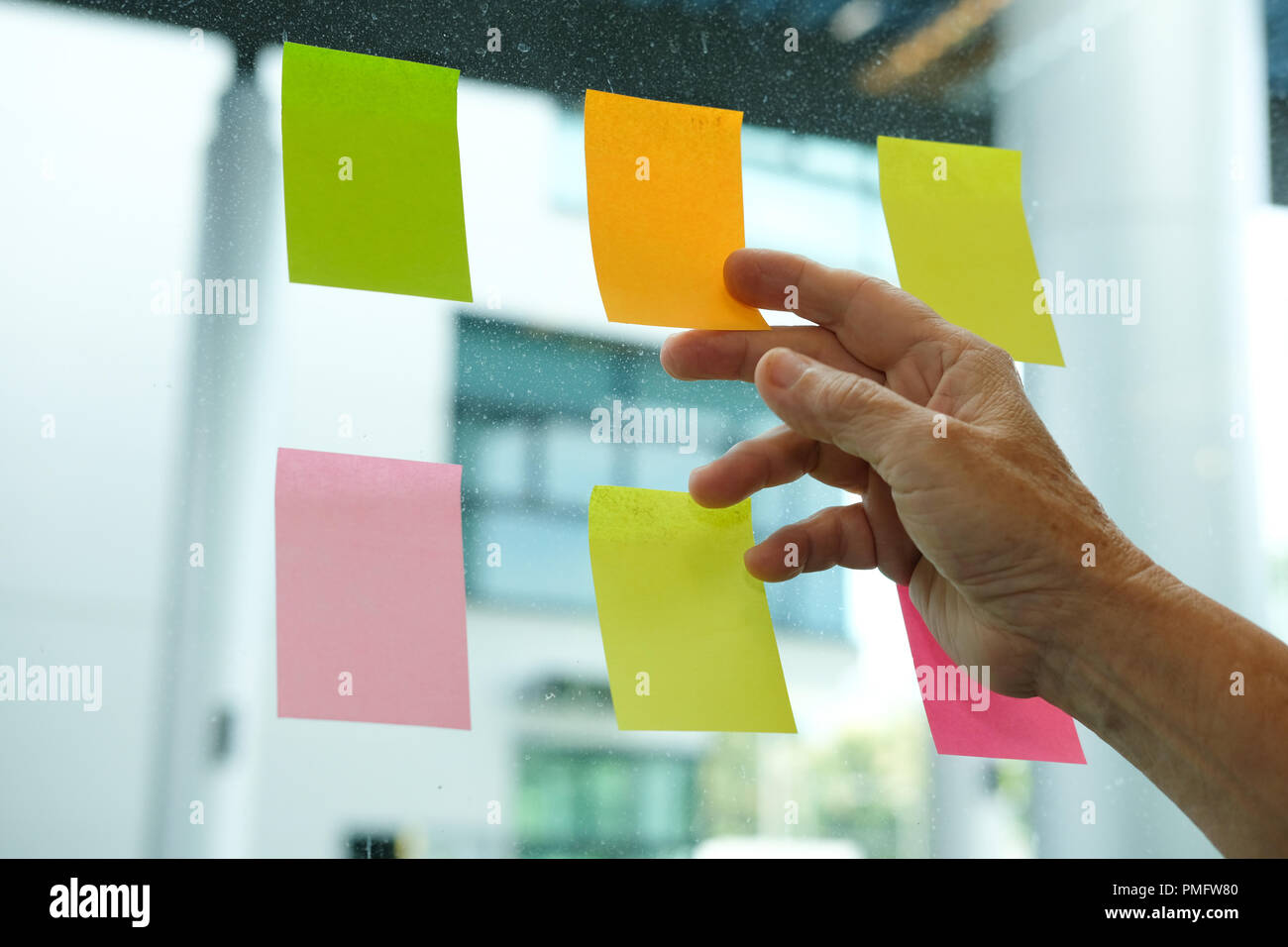 hand hold adhesive notes on glass wall at workplace. Sticky note paper ...