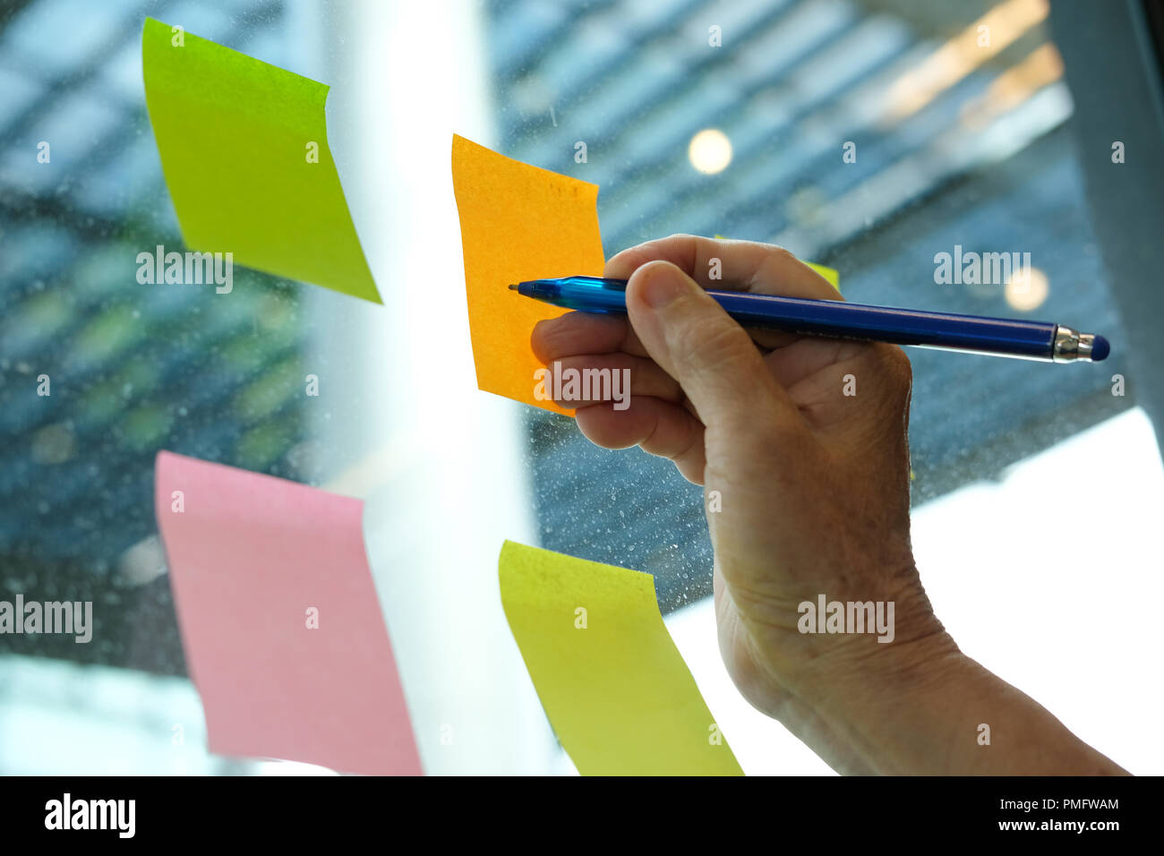 Businessman write on adhesive notes on glass wall at workplace. Sticky ...