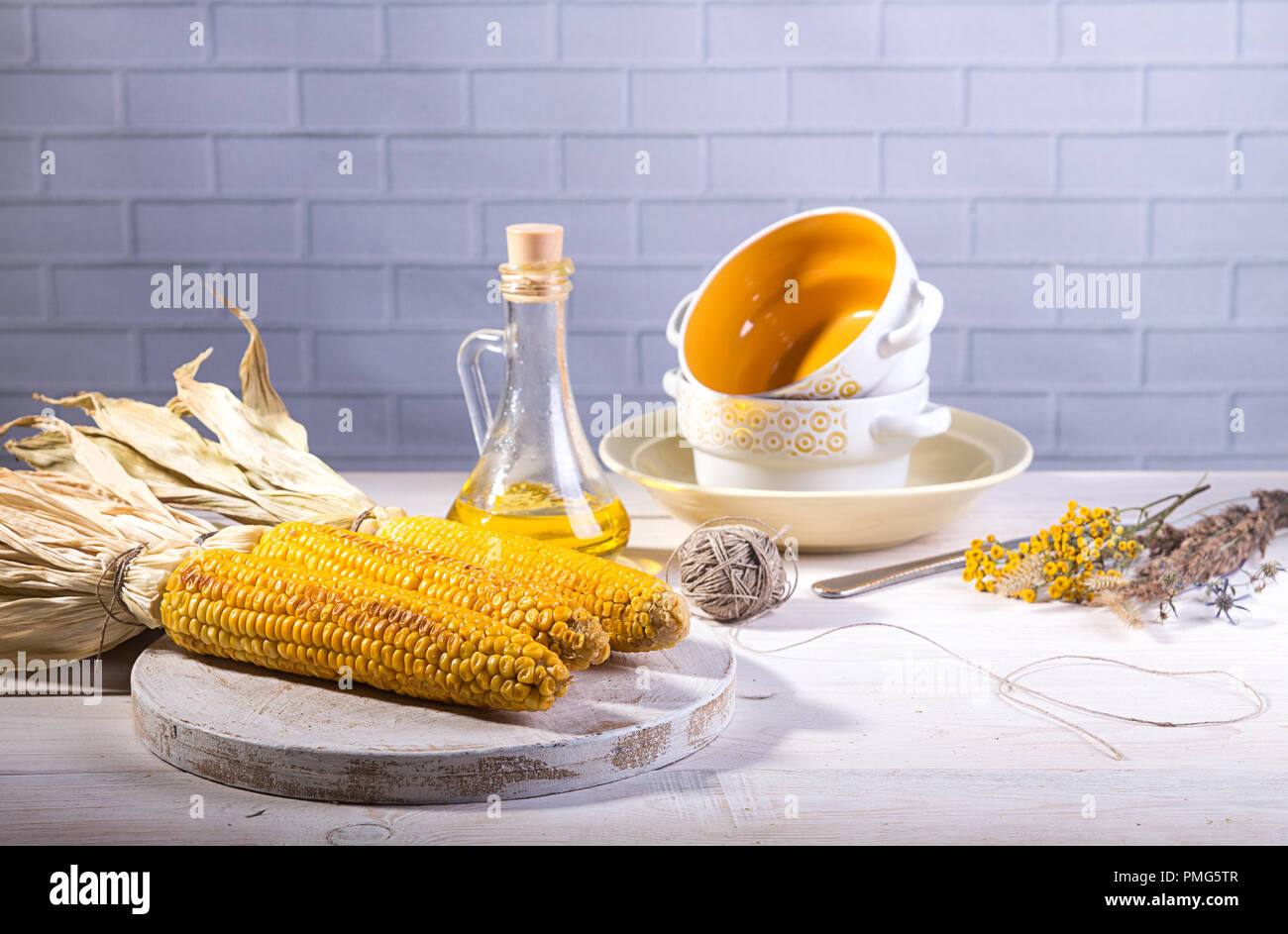 Baked grilled cobs of corn on white brick background Stock Photo - Alamy