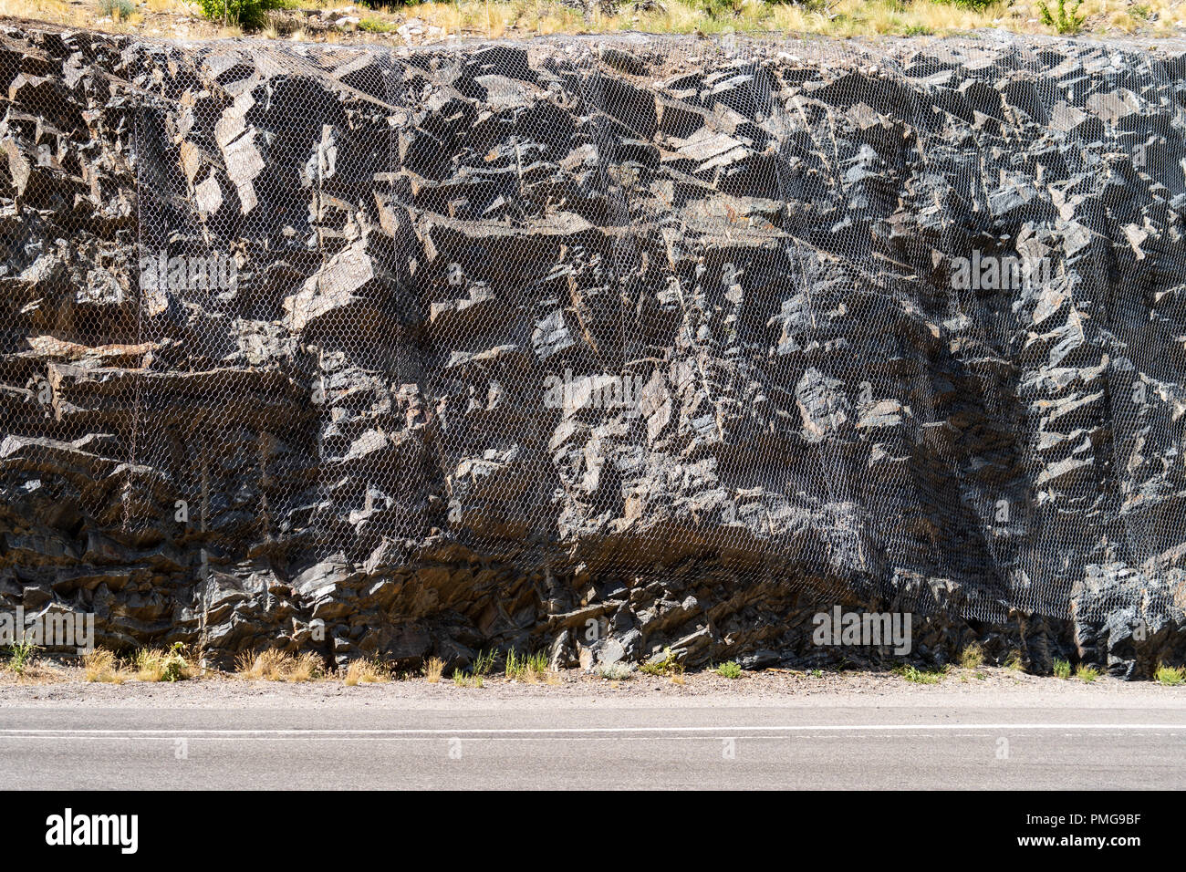 A net placed over rocks along the side of a mountain road prevents a ...