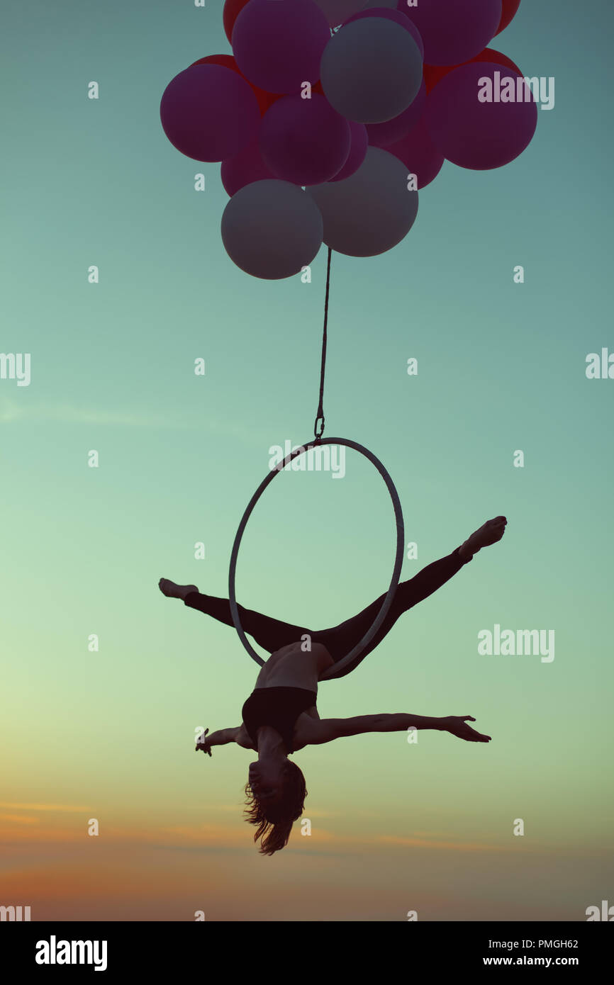 Gymnast girl doing acrobatic tricks on a circle on the setting sun ...