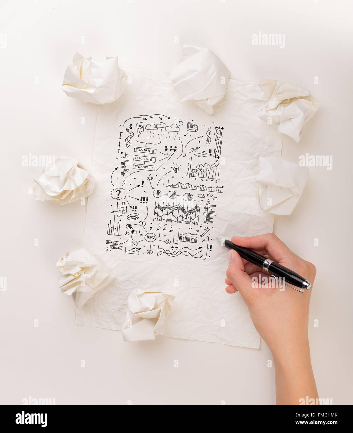 Female hand next to a few crumpled paper balls drawing charts and ...