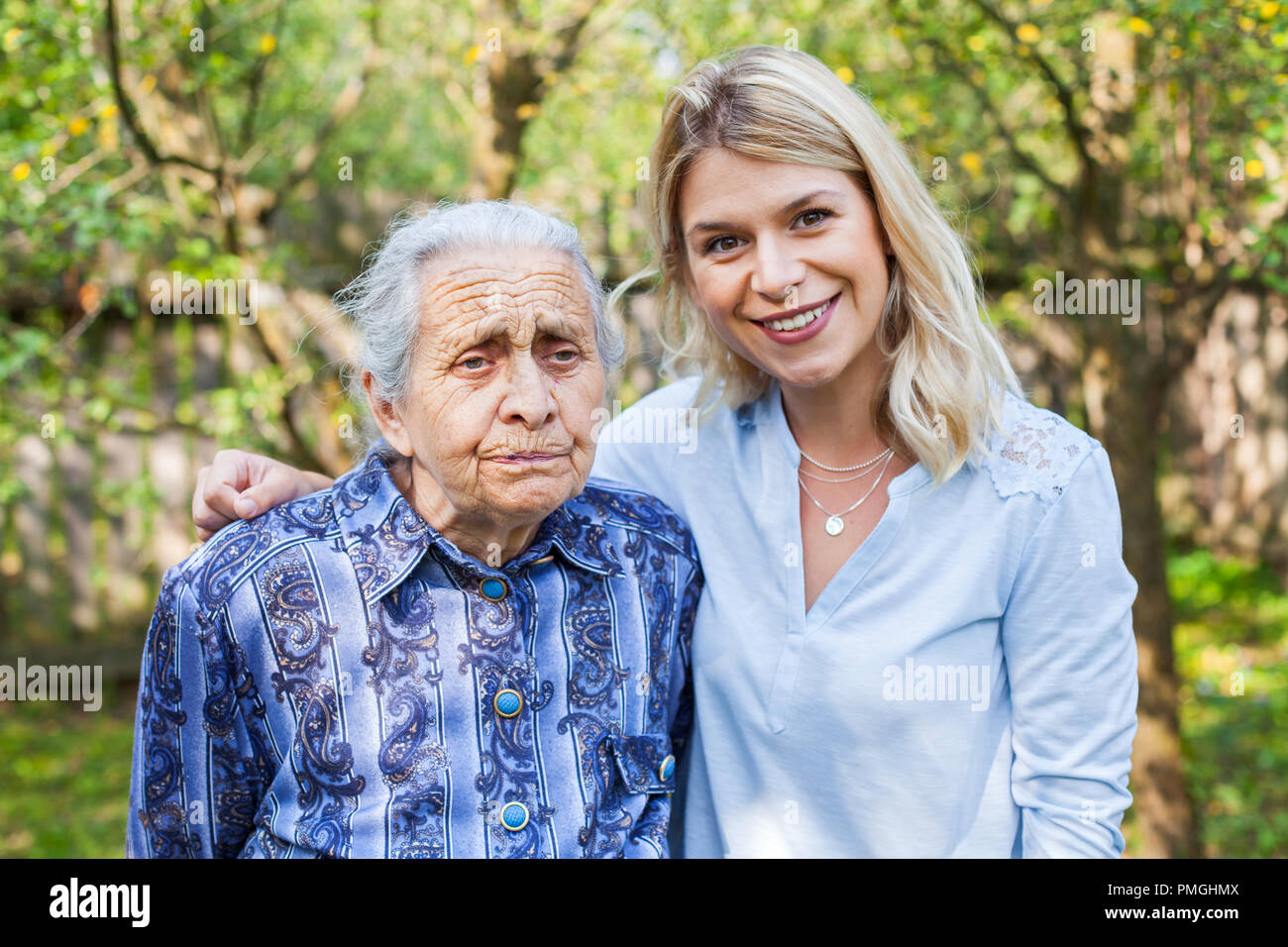 Smiling young caretaker walking with senior lady in the garden Stock ...