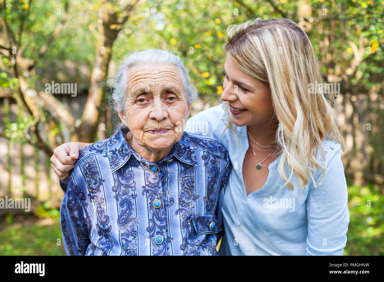 Smiling young caretaker walking with senior lady in the garden Stock ...