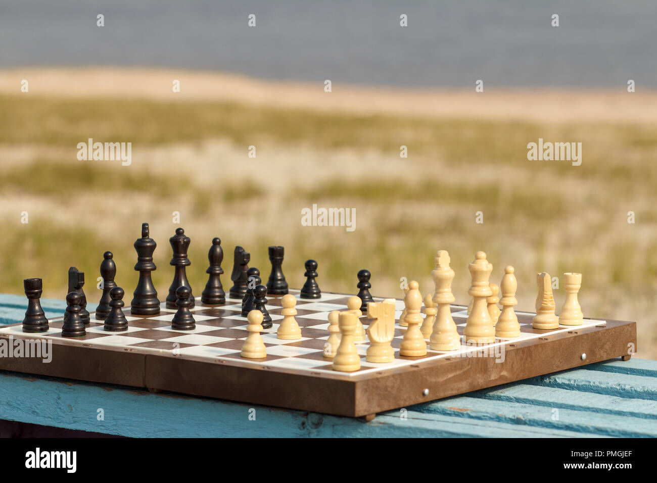 Chess board with chess pieces on wooden bench with river embankment ...