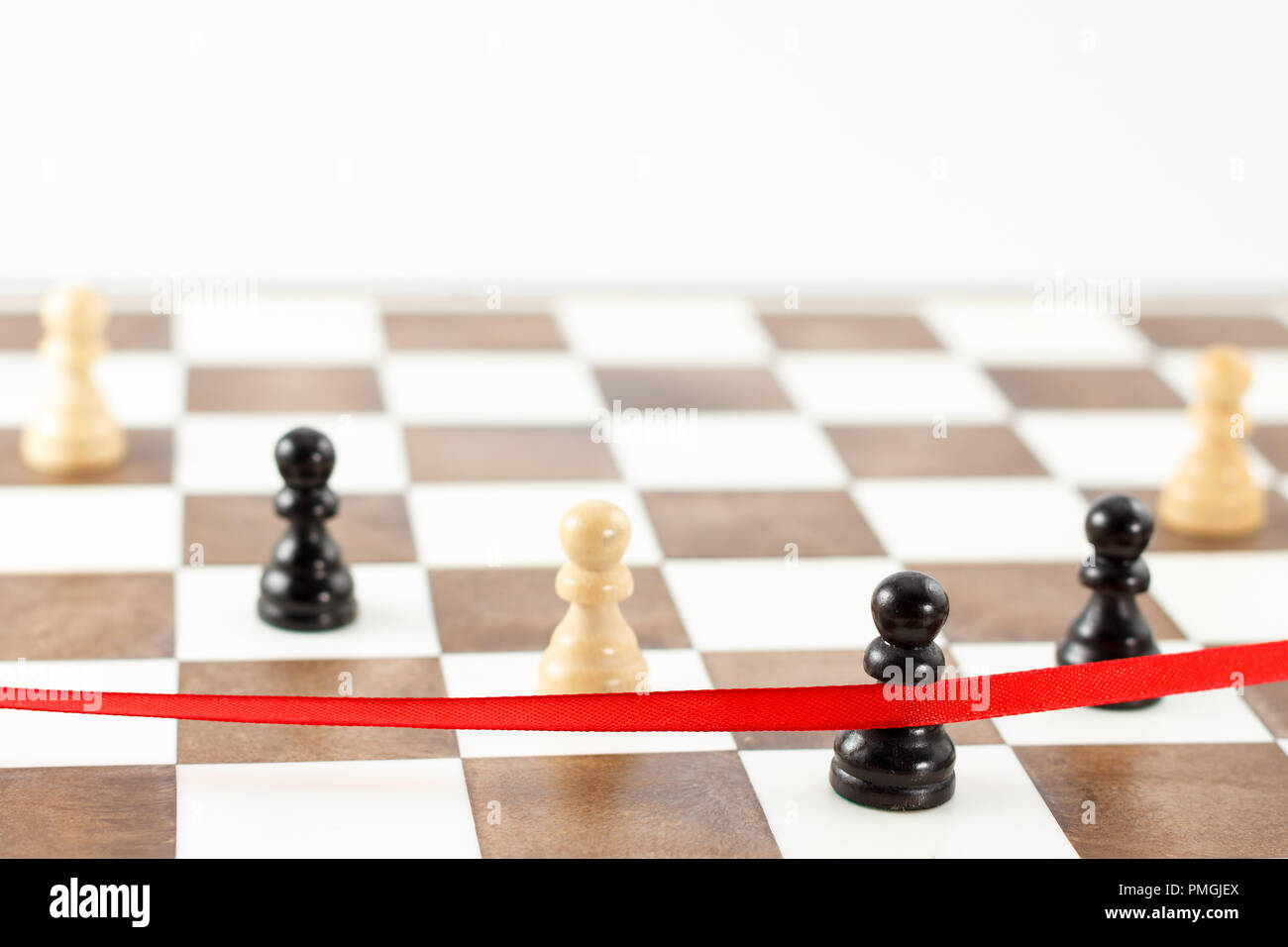 Black pawn's figure crossing the red finish ribbon. Chess leadership ...