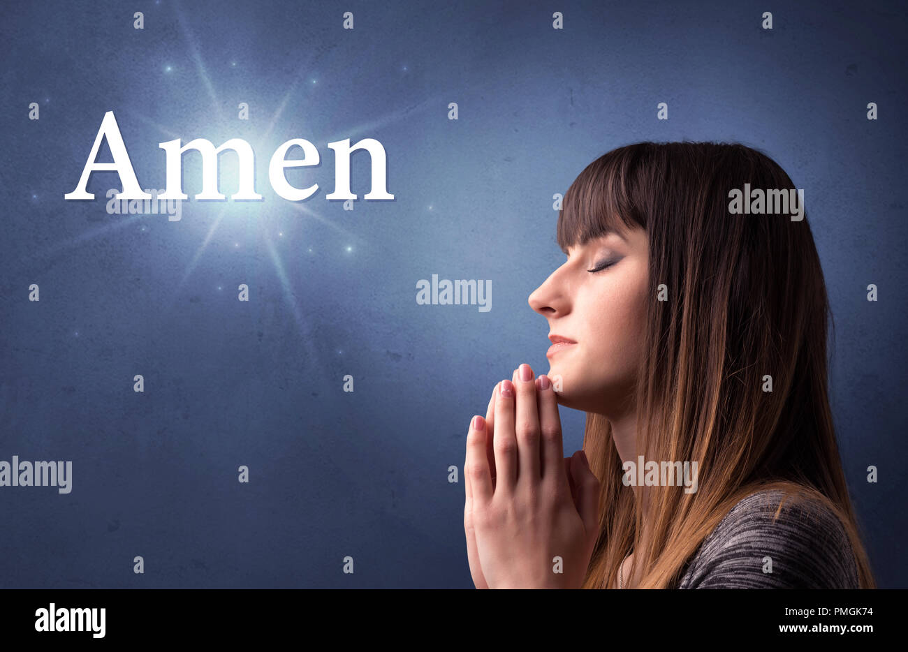 Young woman praying on a blue background with the word Amen written ...