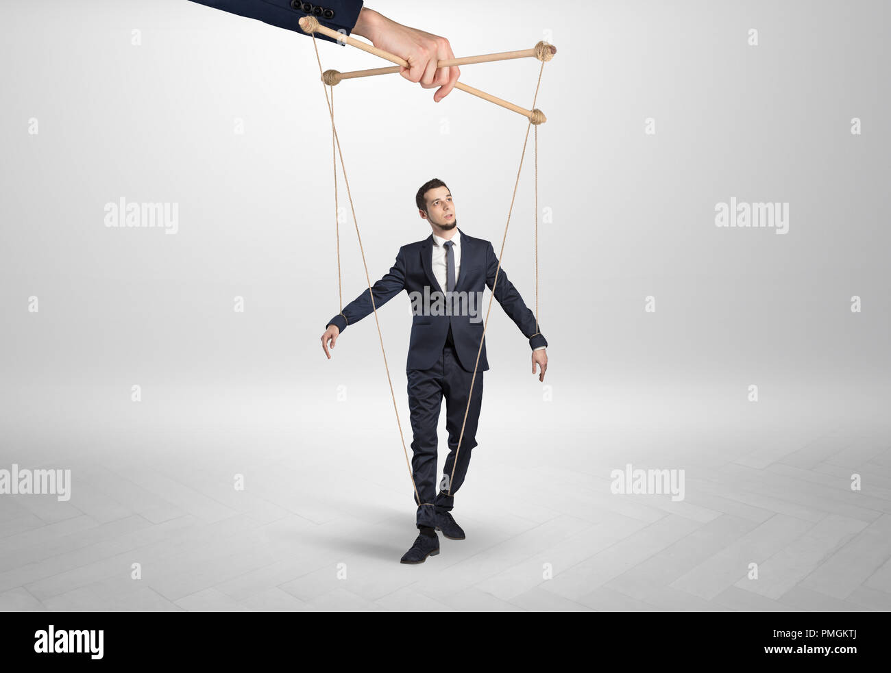 Puppet businessman in an empty room leaded by a huge hand Stock Photo ...