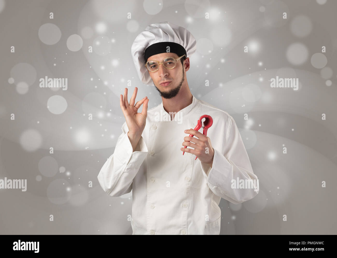 Male cook with kitchen tools and shiny grey wallpaper Stock Photo - Alamy