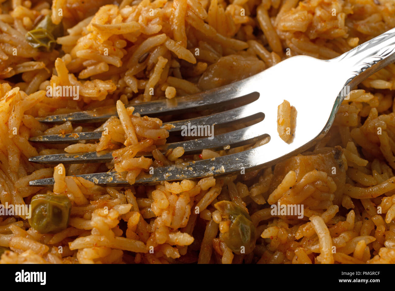 A fork atop a serving of spicy vegetable rice illuminated with window ...