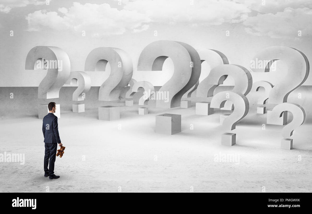 Businessman standing and looking to a bunch of question mark signs ...