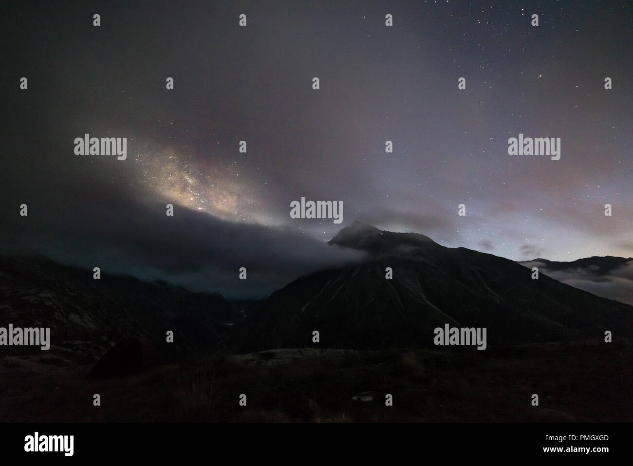 Wanderlust by night on the Alps with clouds and fog. Snowy mountains ...