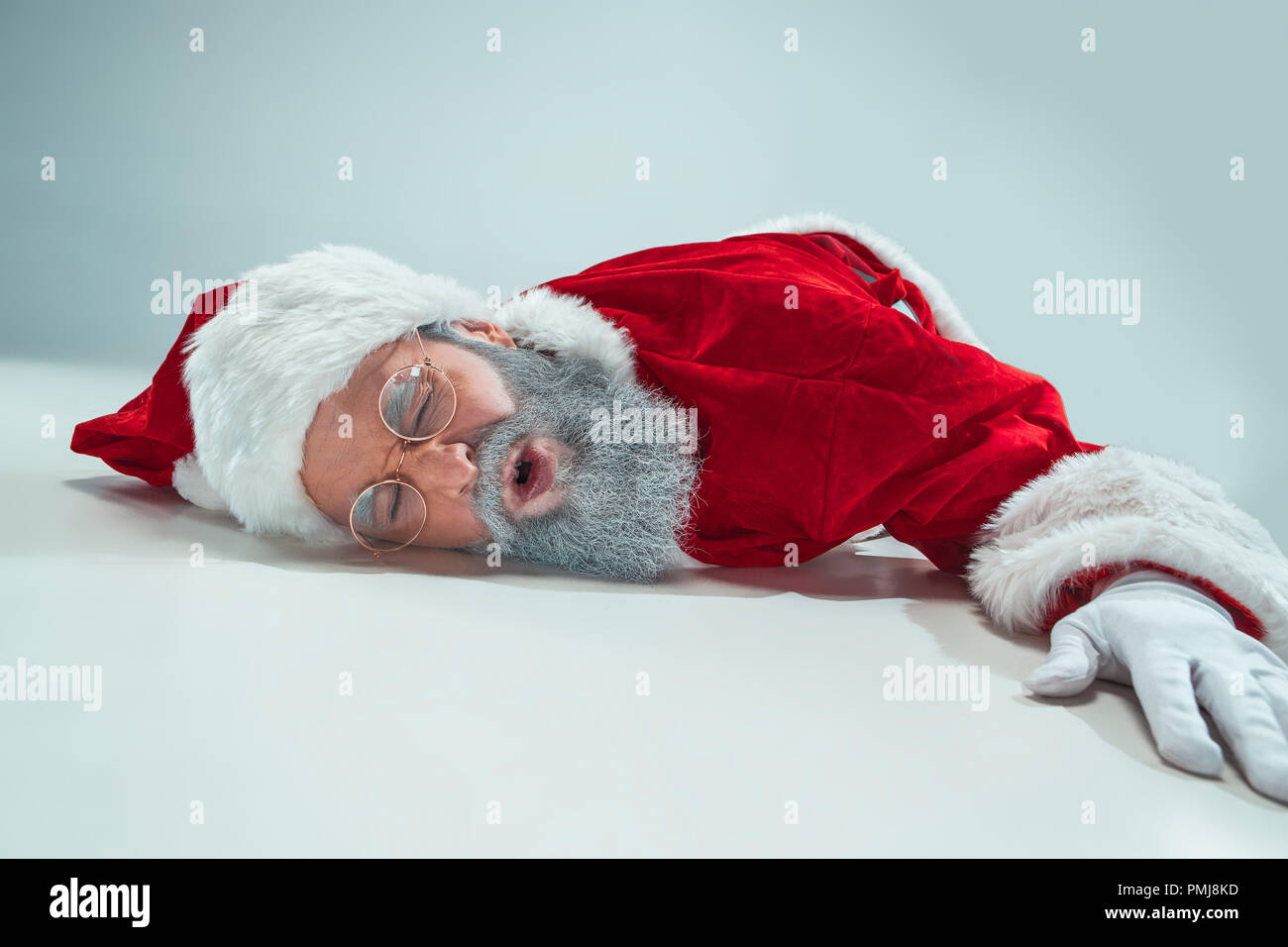 The tired Santa Claus lying on floor on white studio background. Man ...
