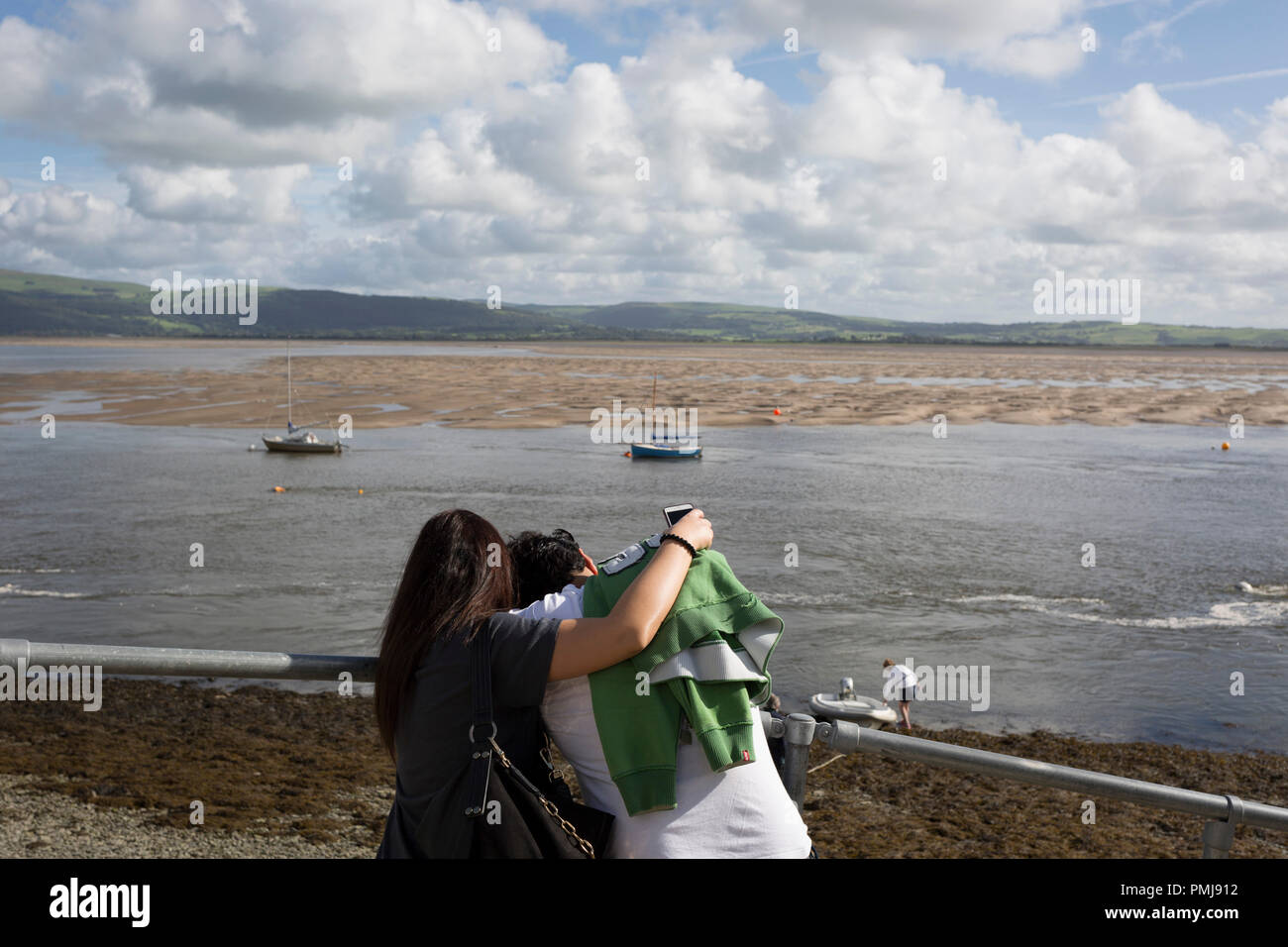 A couple hug while looking out across the estuary at low-tide of the ...