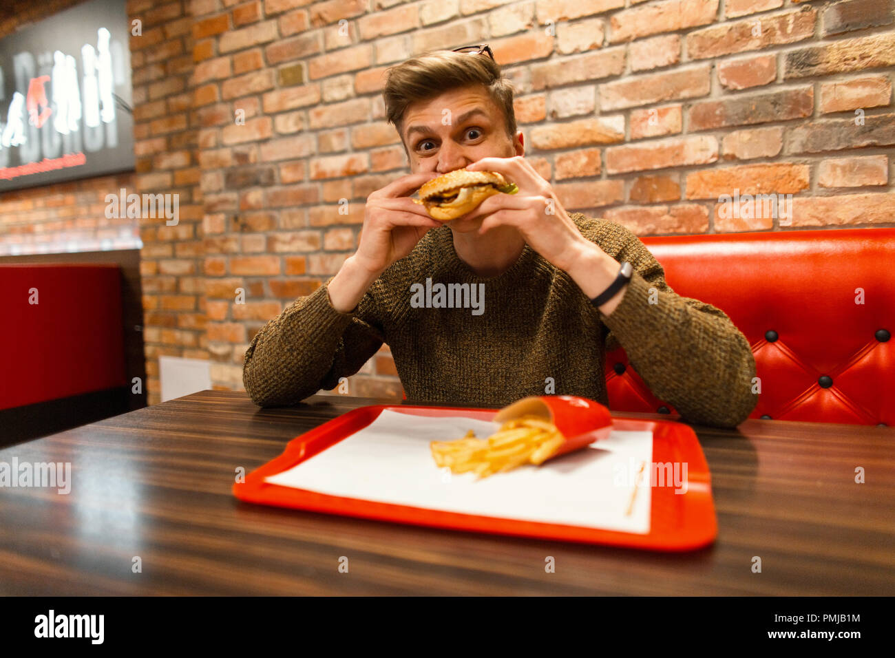 Handsome young man eats fast food. Hamburger and French fries Stock ...