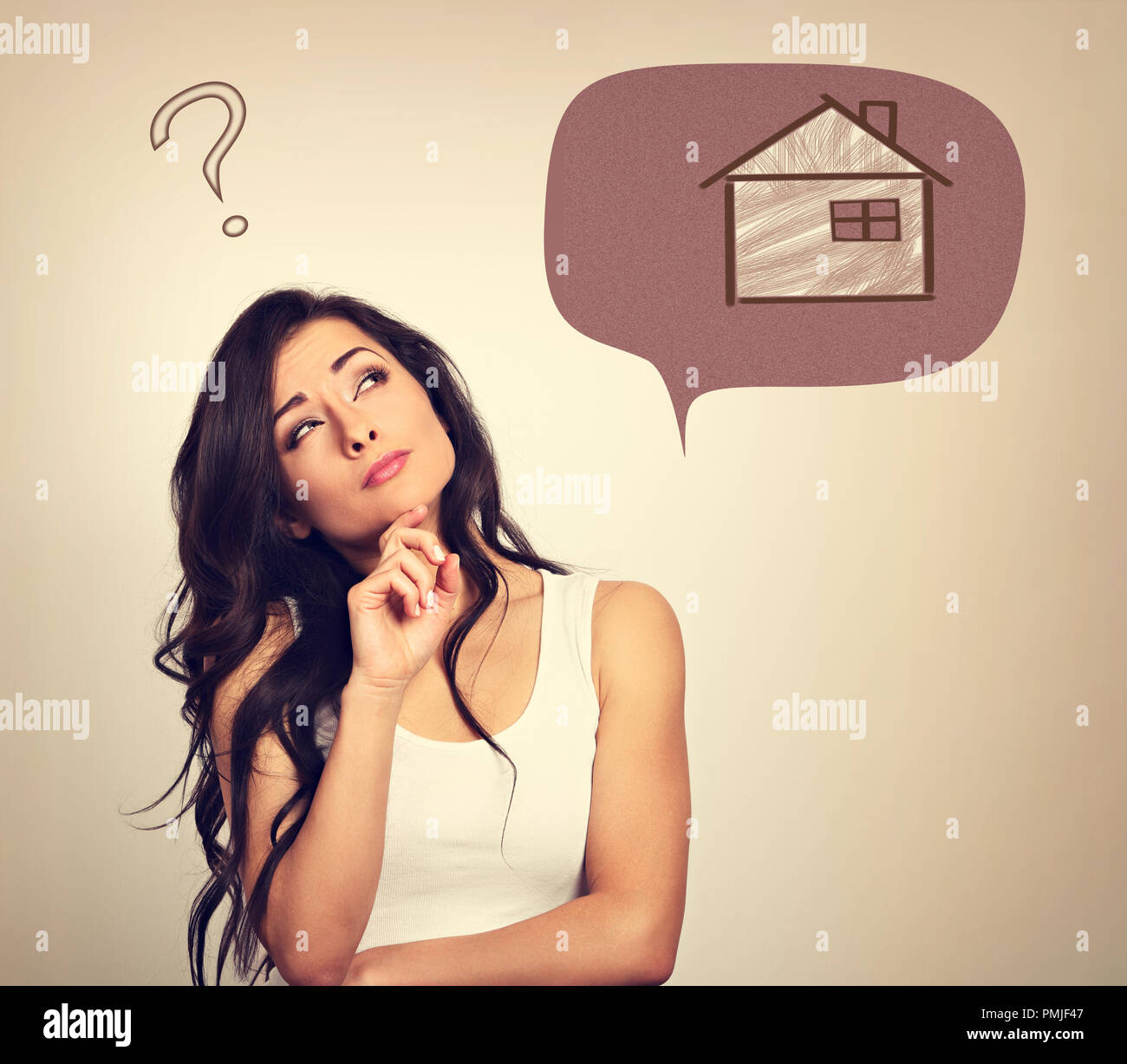 Beautiful serious thinking woman looking up on small illustration house ...