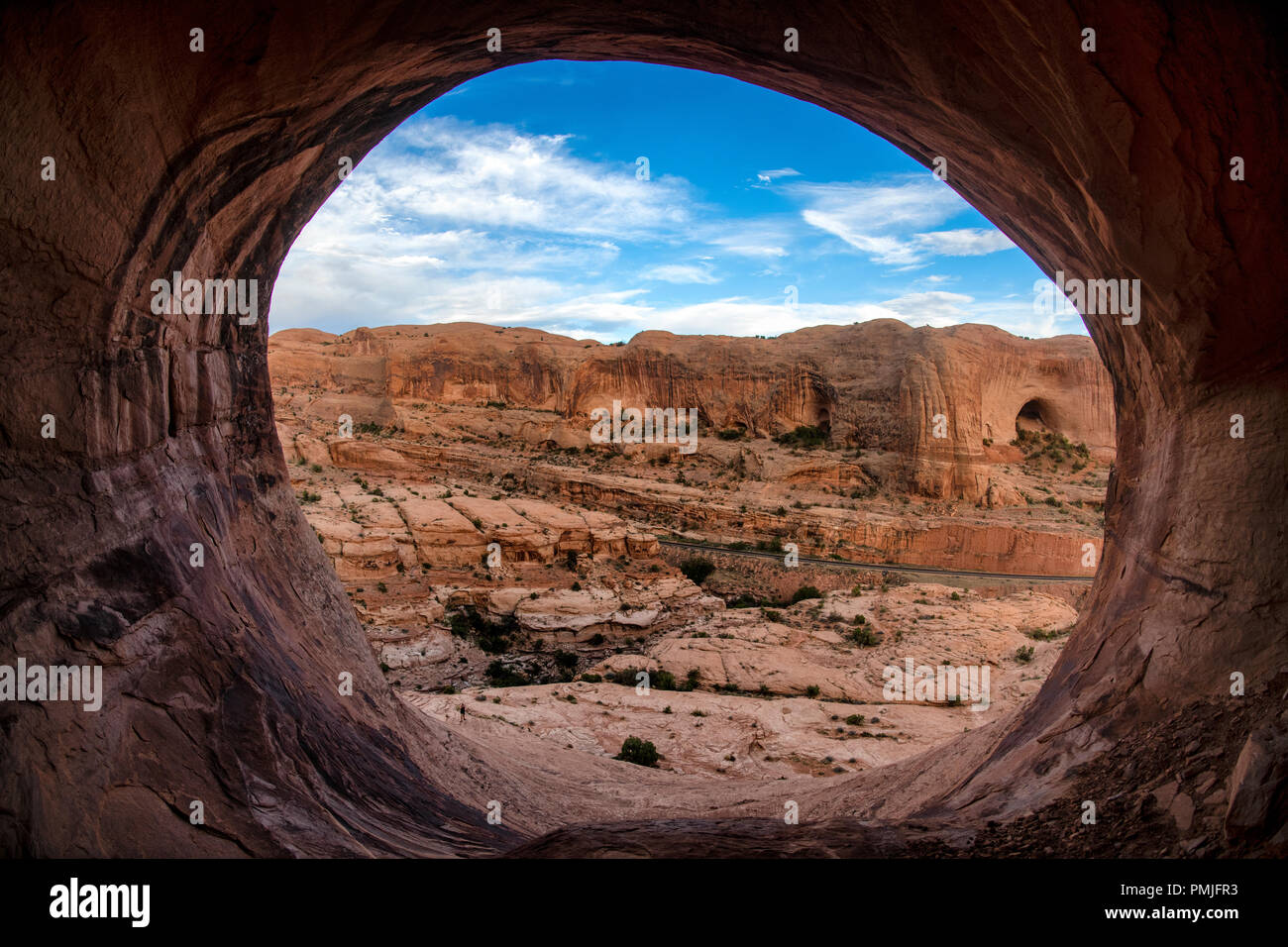 The view looking out of a cave high above the trail to Corona Arch ...