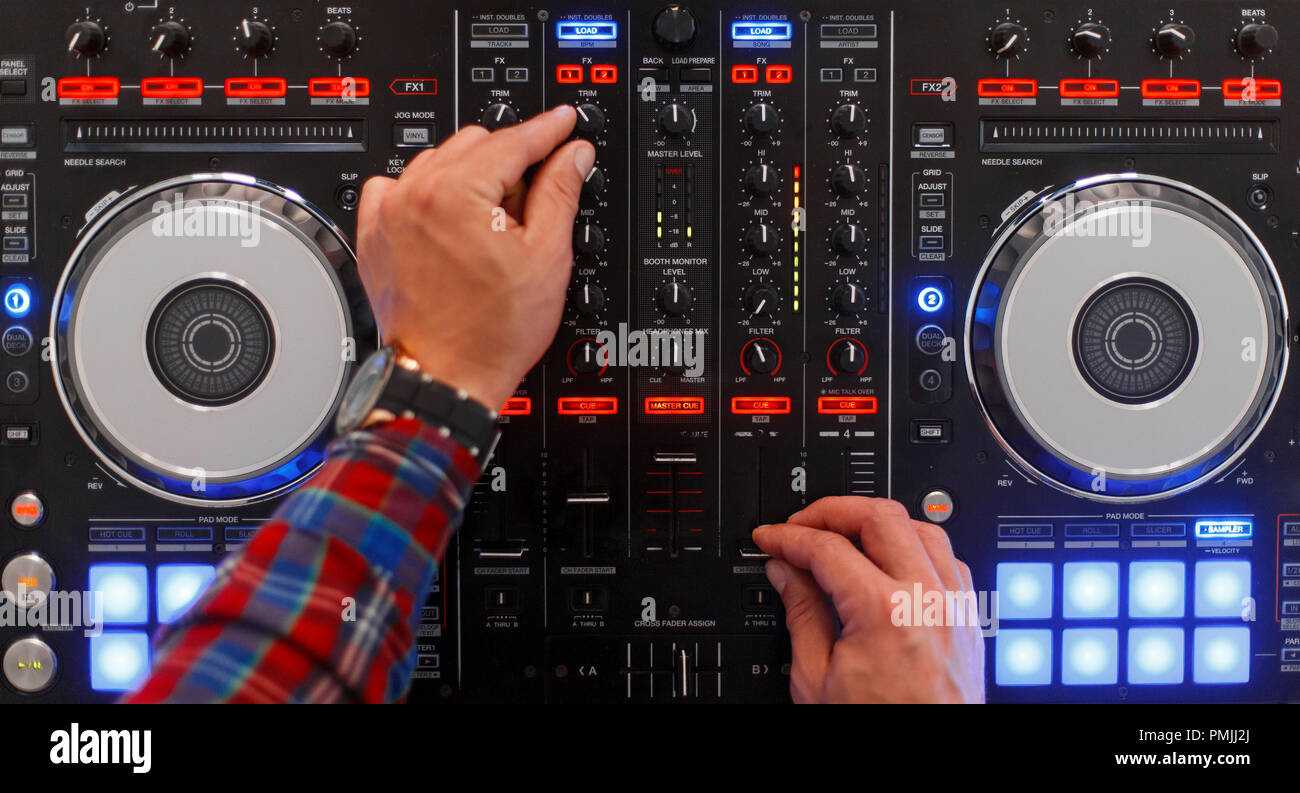 DJ in the process of work. Men's hands are played on the mixing console ...