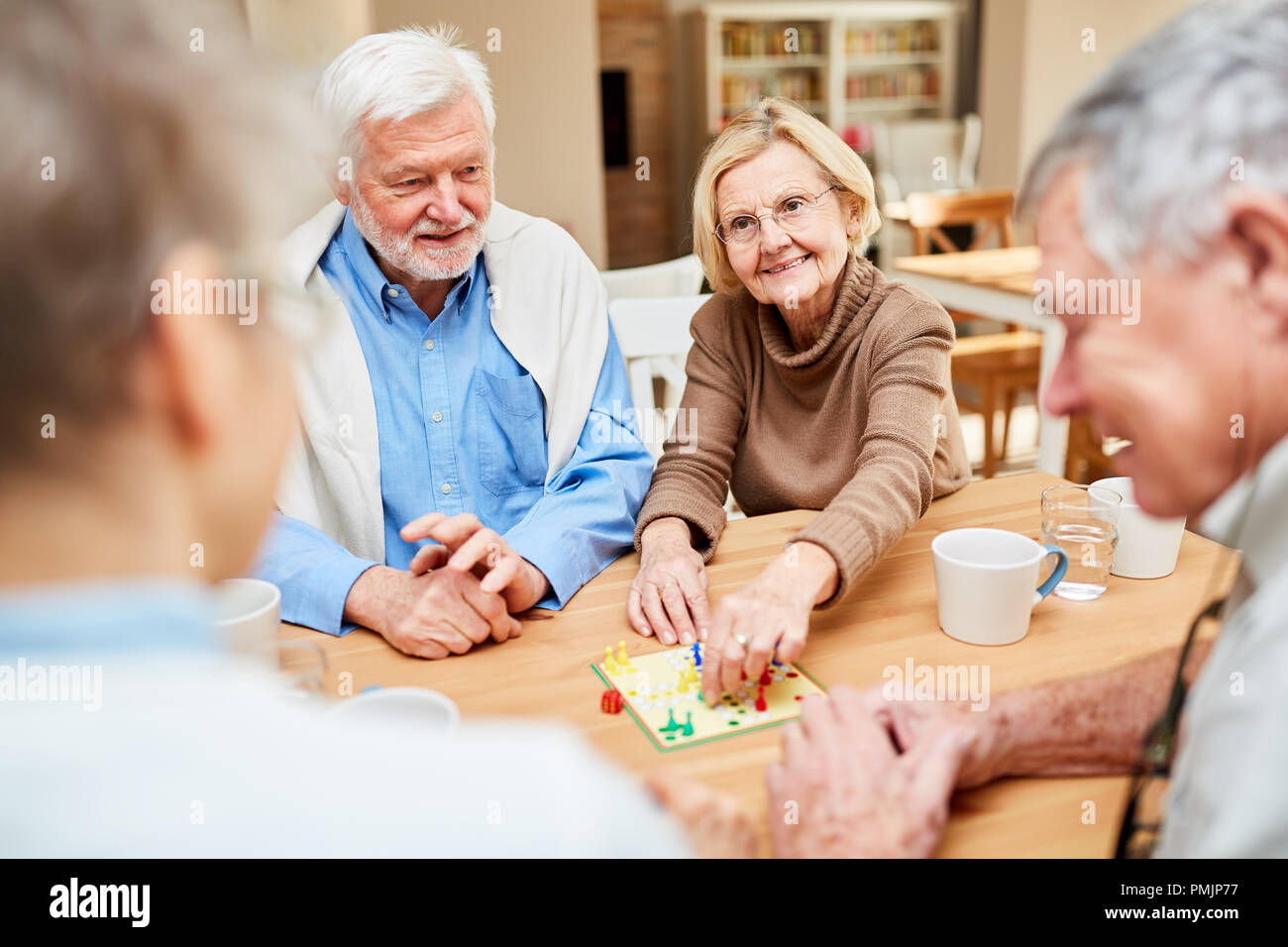 Senior couple and friends have fun playing board game in retirement ...