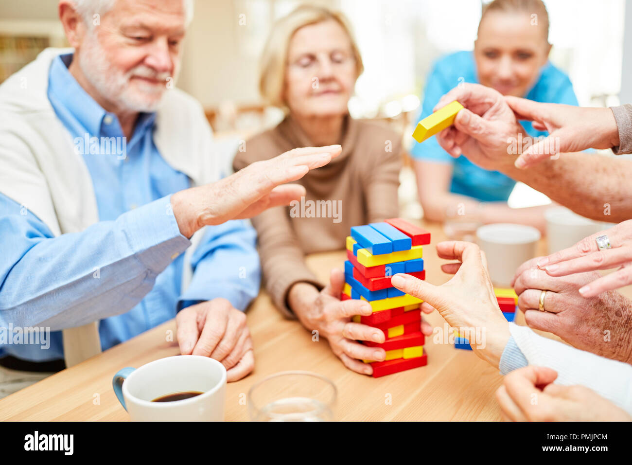 Seniors with dementia build together tower of colorful building blocks ...